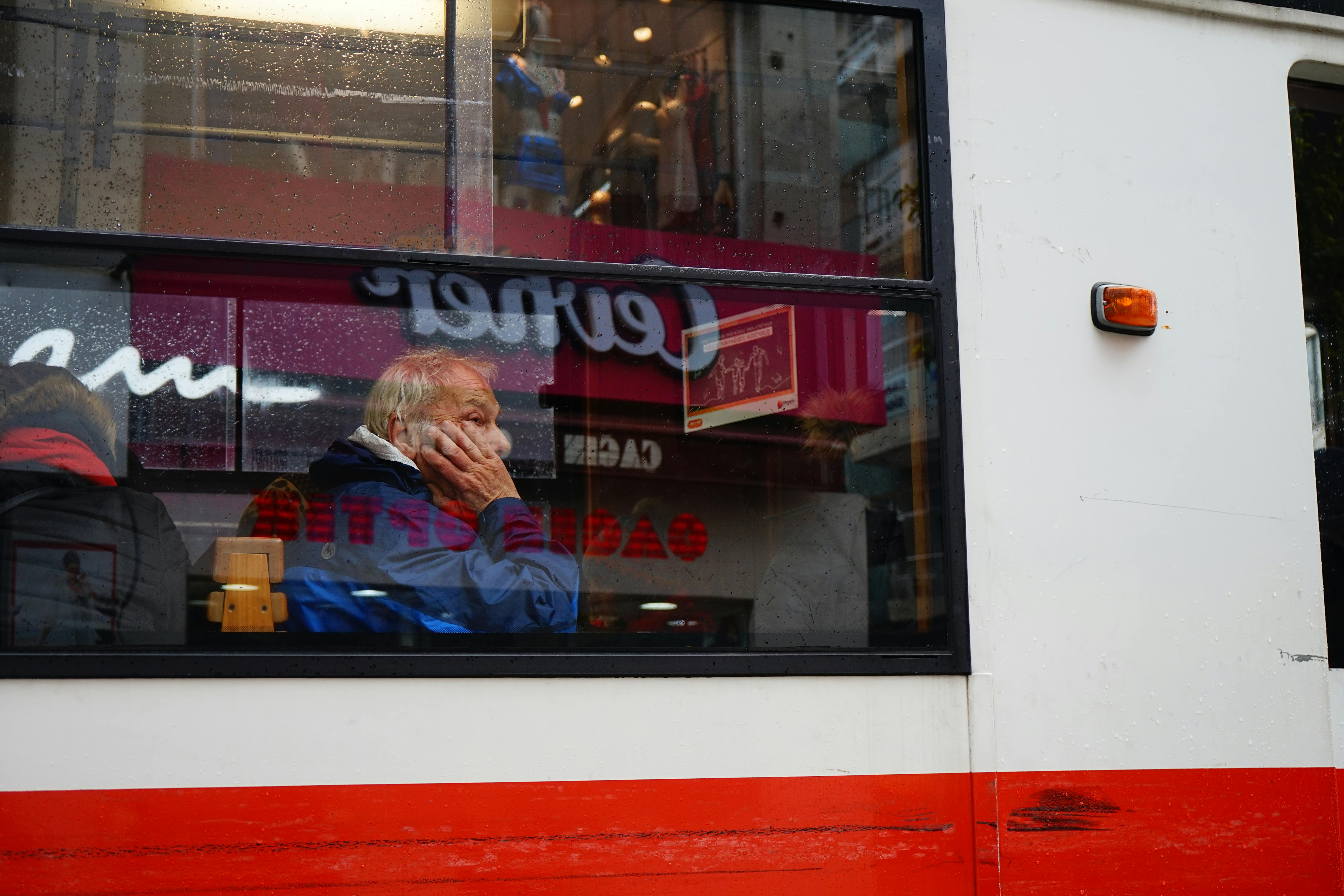 A Man Looking Afar while Sitting Near the Glass Window · Free Stock Photo