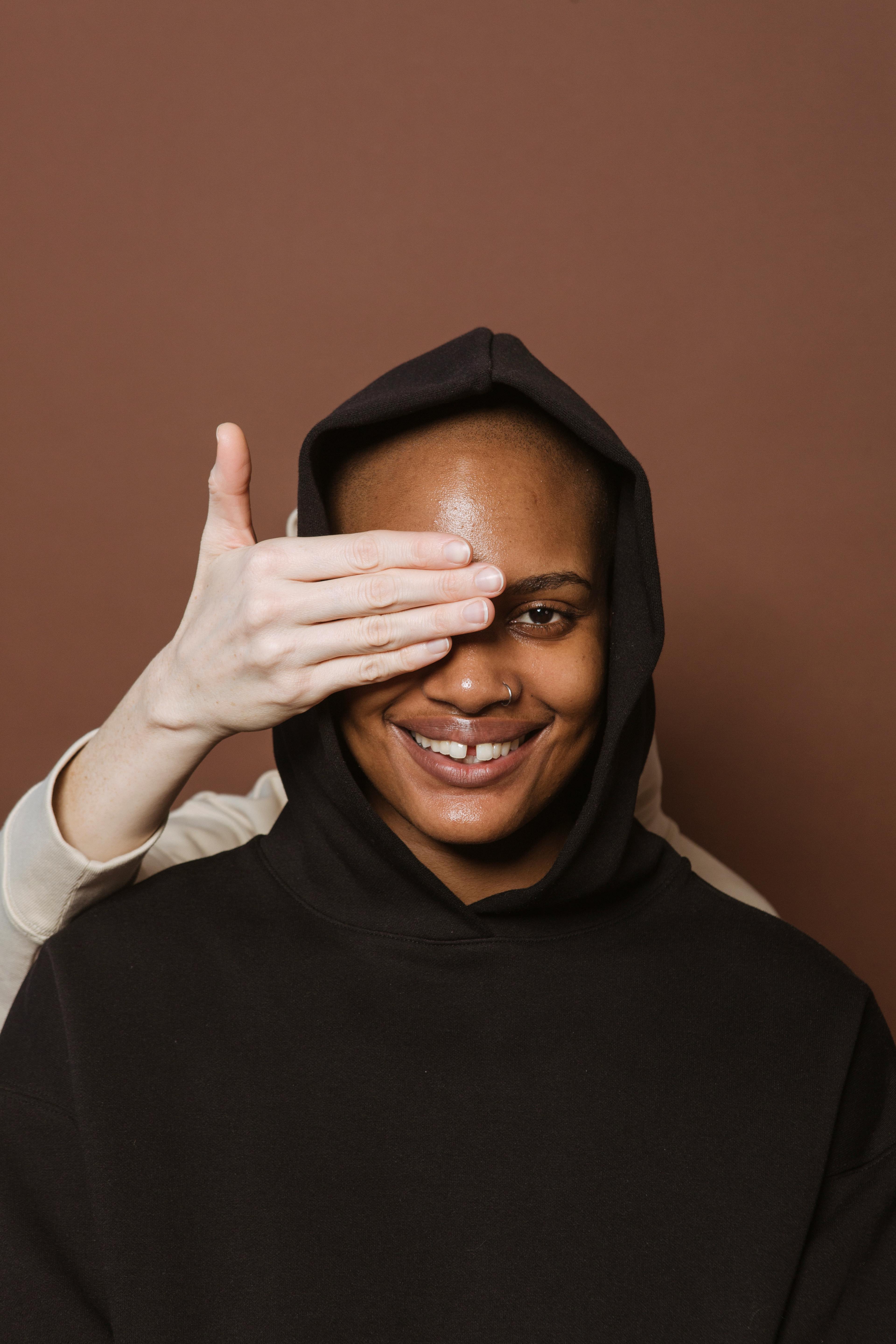 Faceless person covering eye of black woman · Free Stock Photo