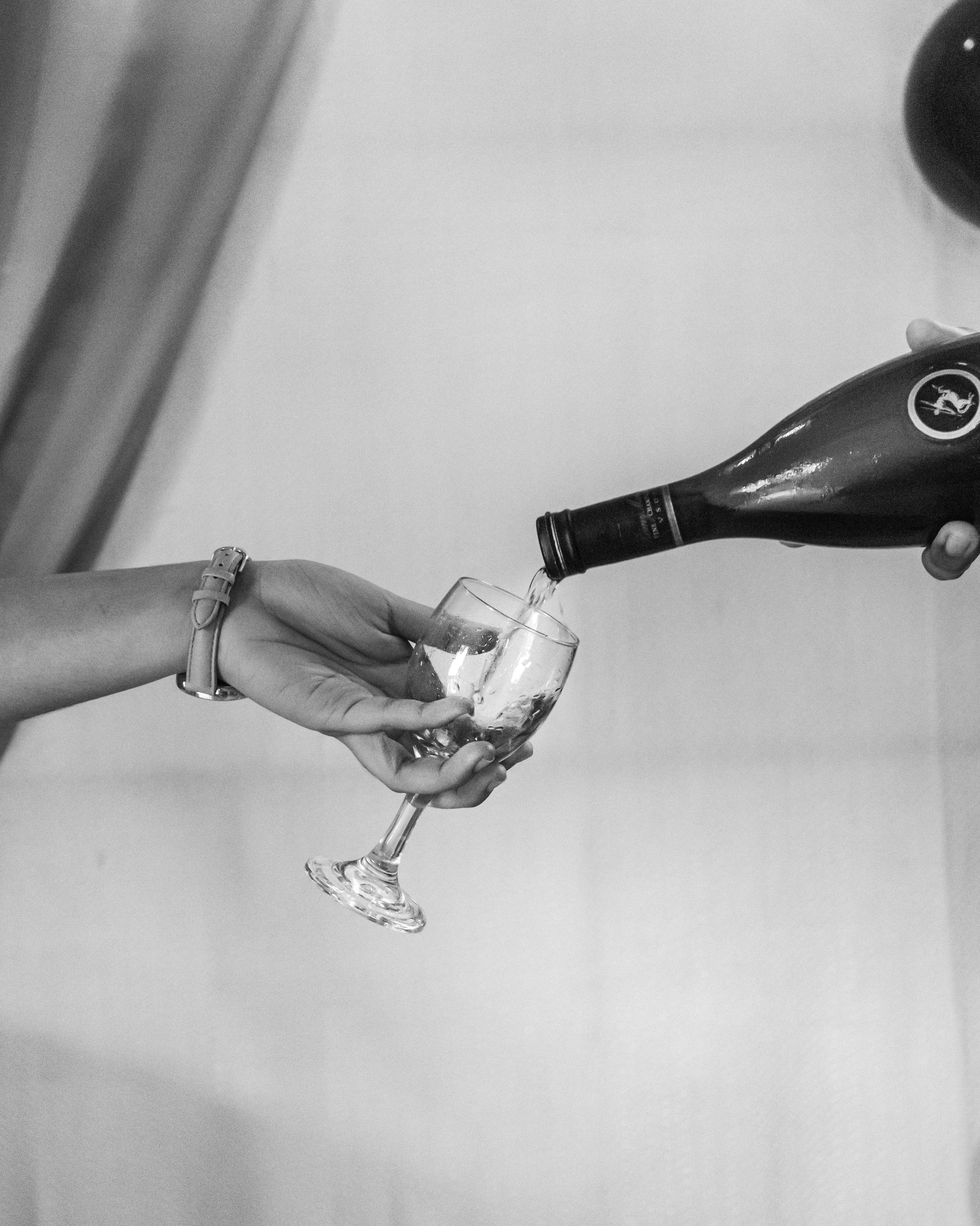 Grayscale Photo of an Alcoholic Beverage Being Poured on a Wine Glass ...