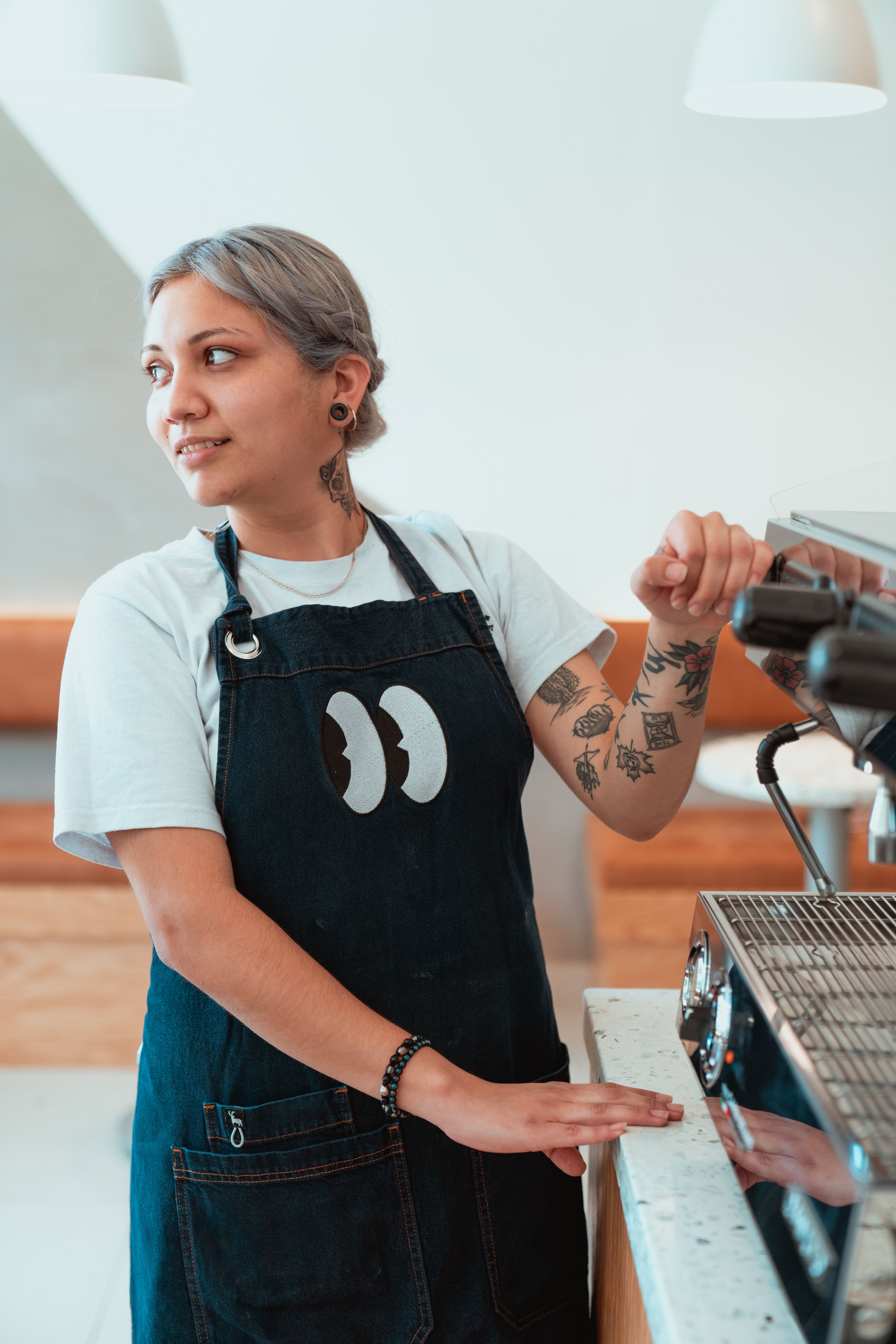 Female barista in beanie and apron resting chin on had · Free Stock Photo