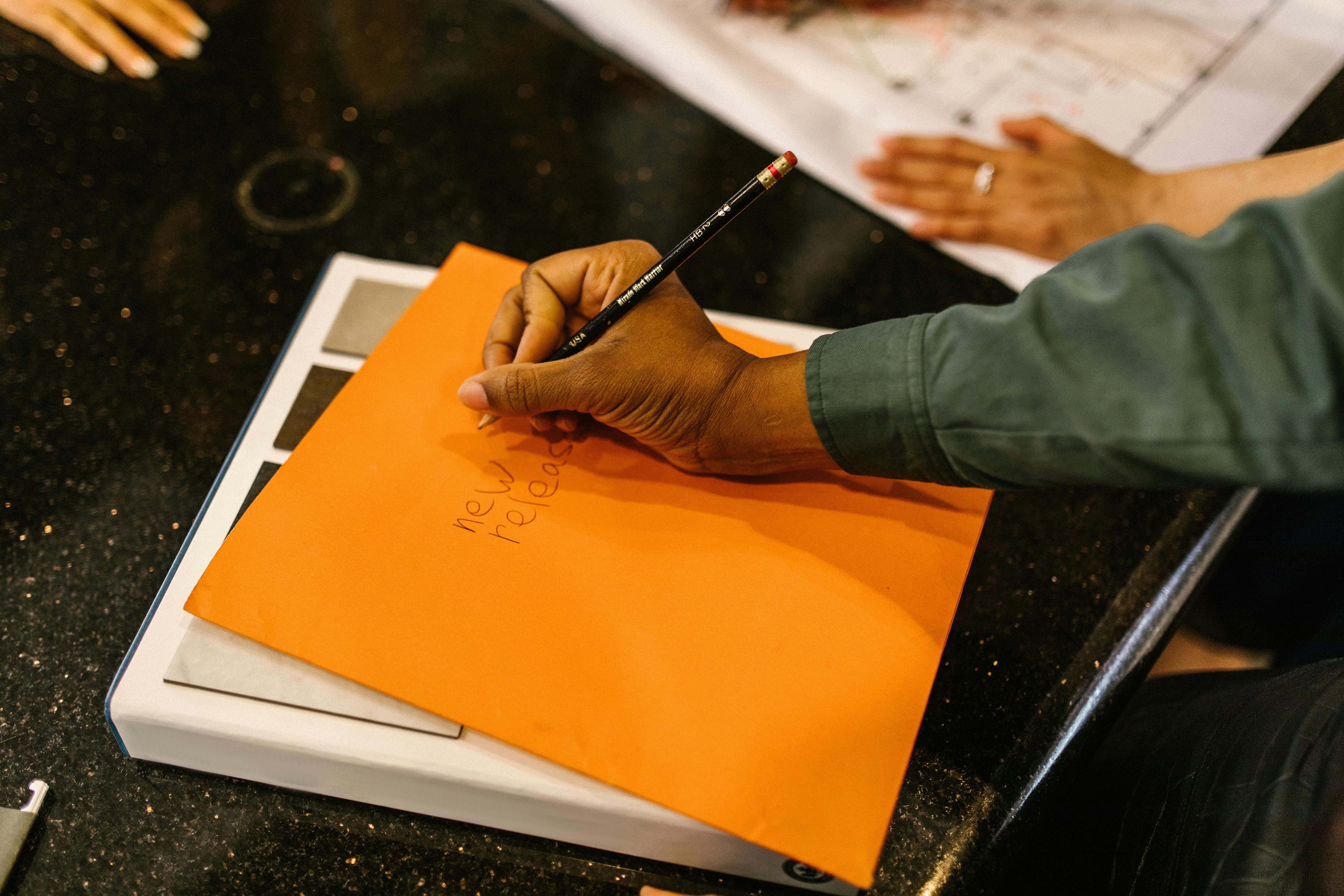 A Person Holding a Pencil while Writing on the Paper · Free Stock Photo