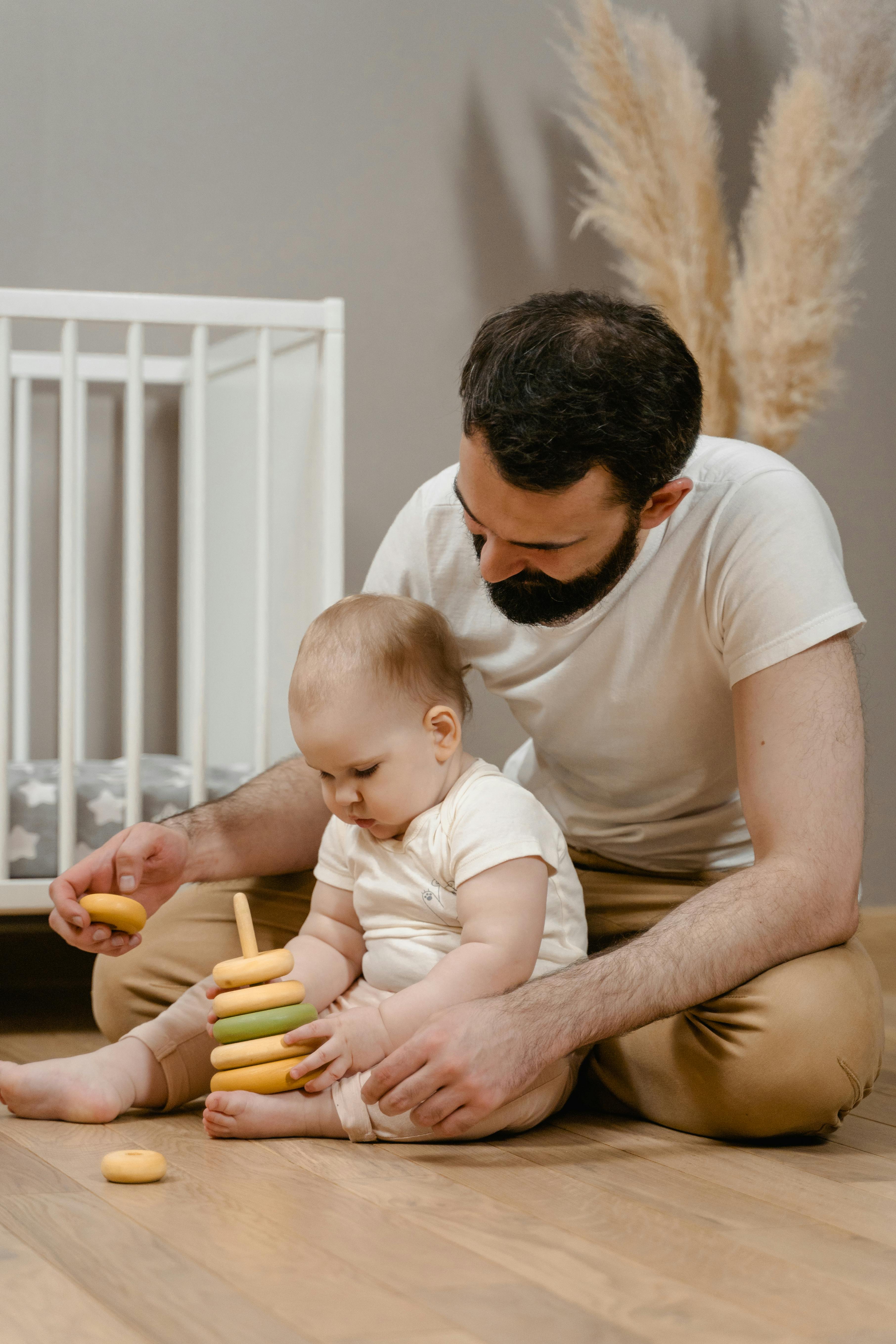 A Man Playing with His Baby while Sitting on the Floor · Free Stock Photo