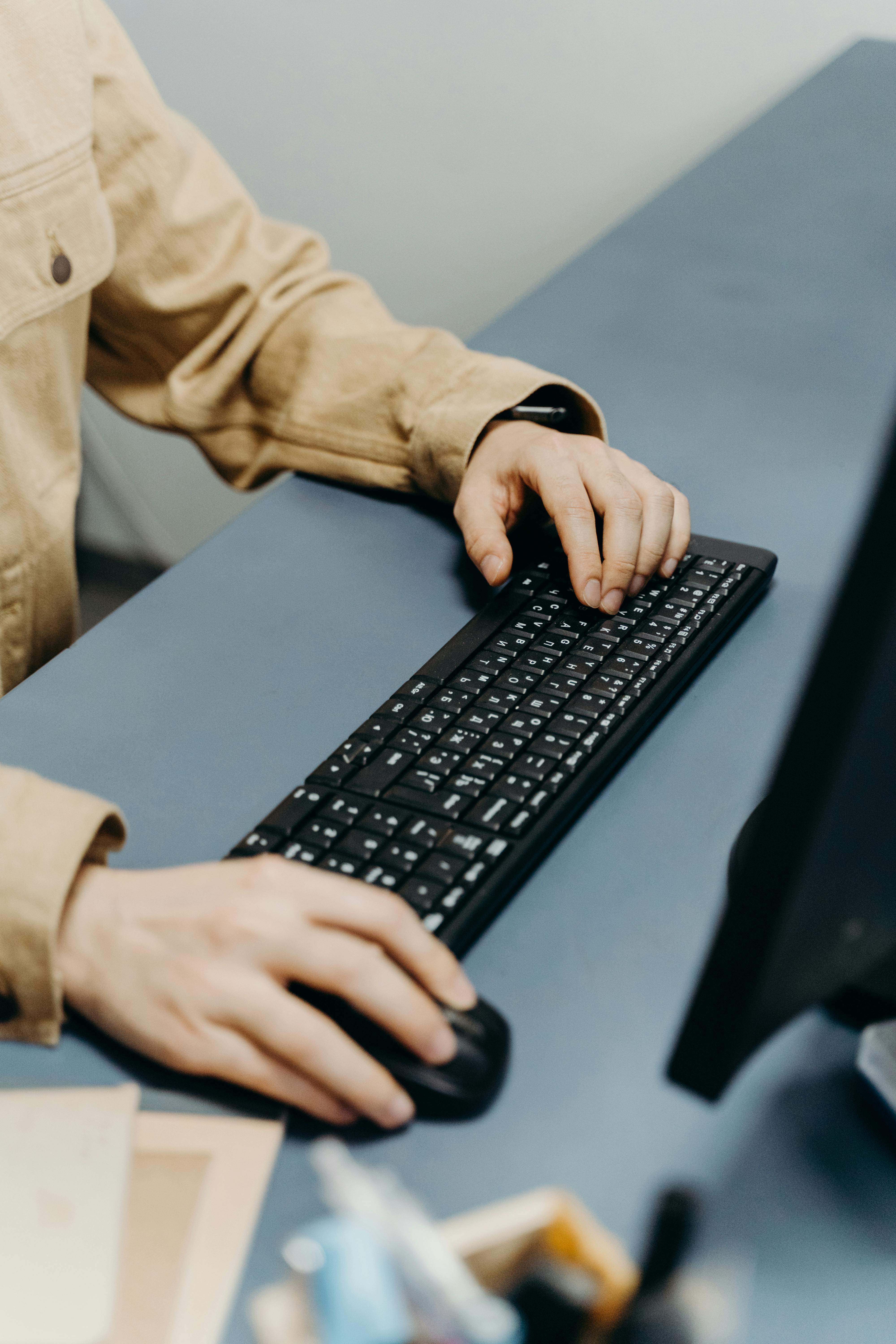A Person in Beige Coat Holding Black Computer Keyboard · Free Stock Photo