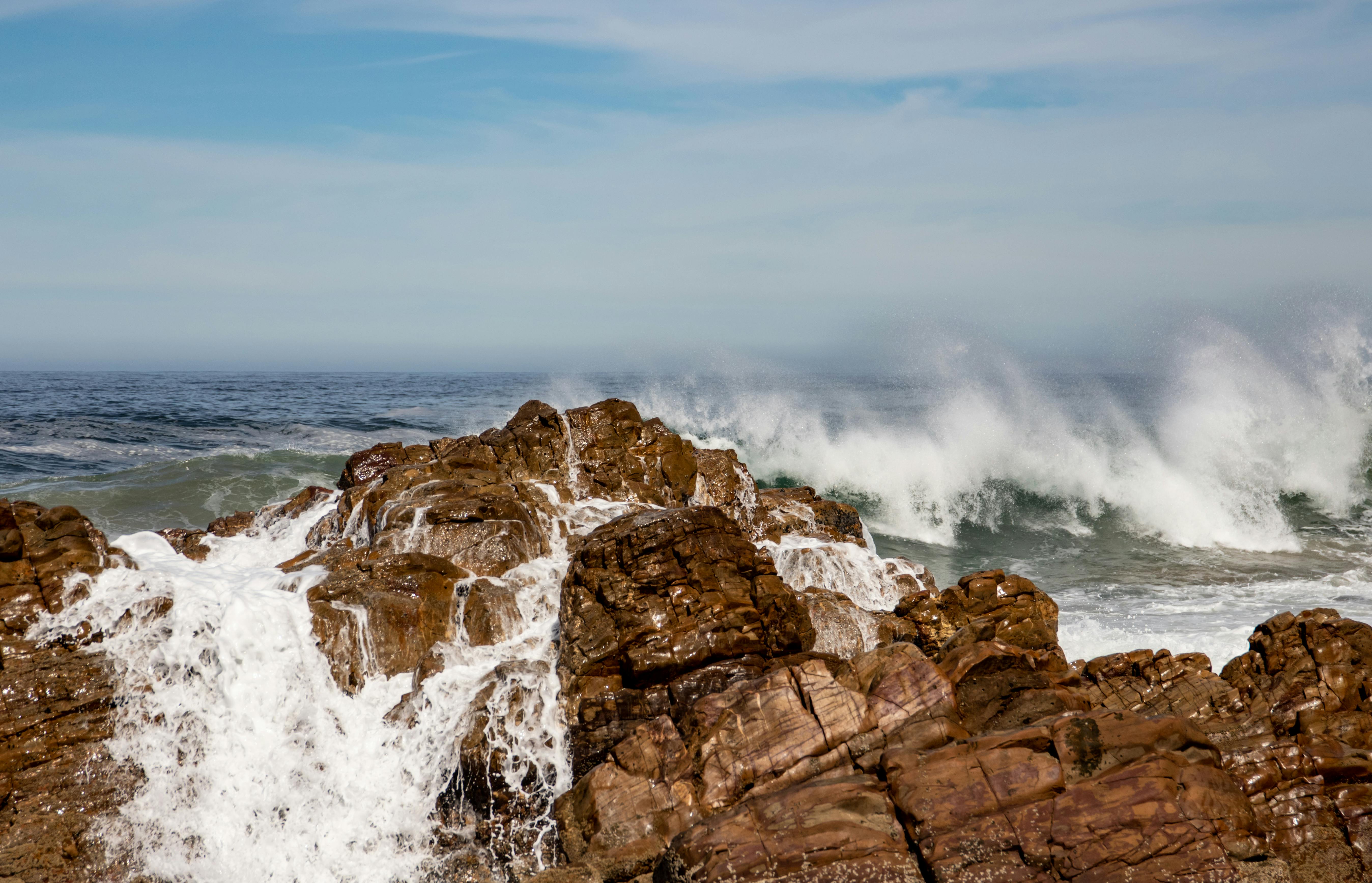 Rough rocks against foamy ocean in stormy weather · Free Stock Photo