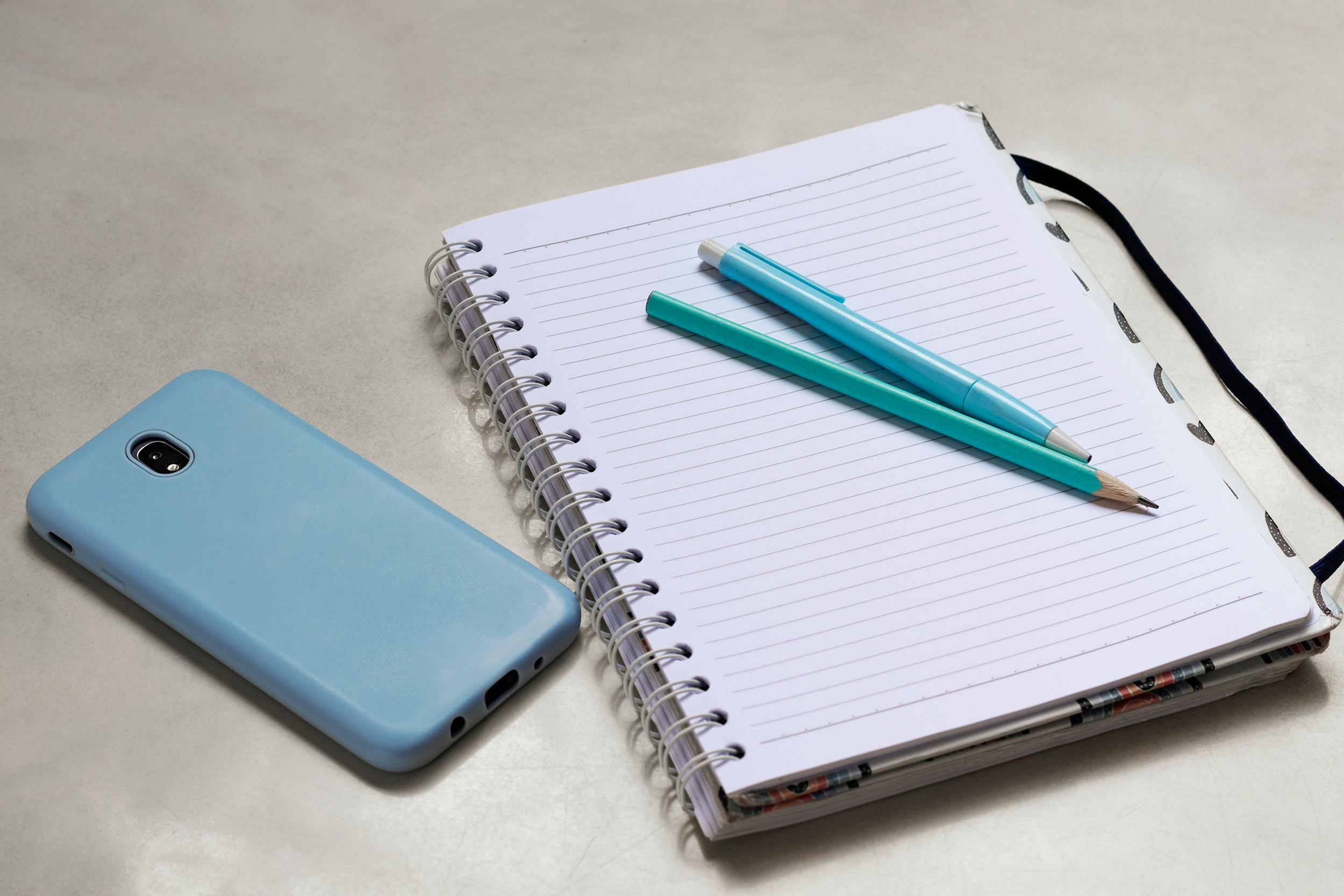 Green Spring Bind Book Beside 2 Blue Pens · Free Stock Photo