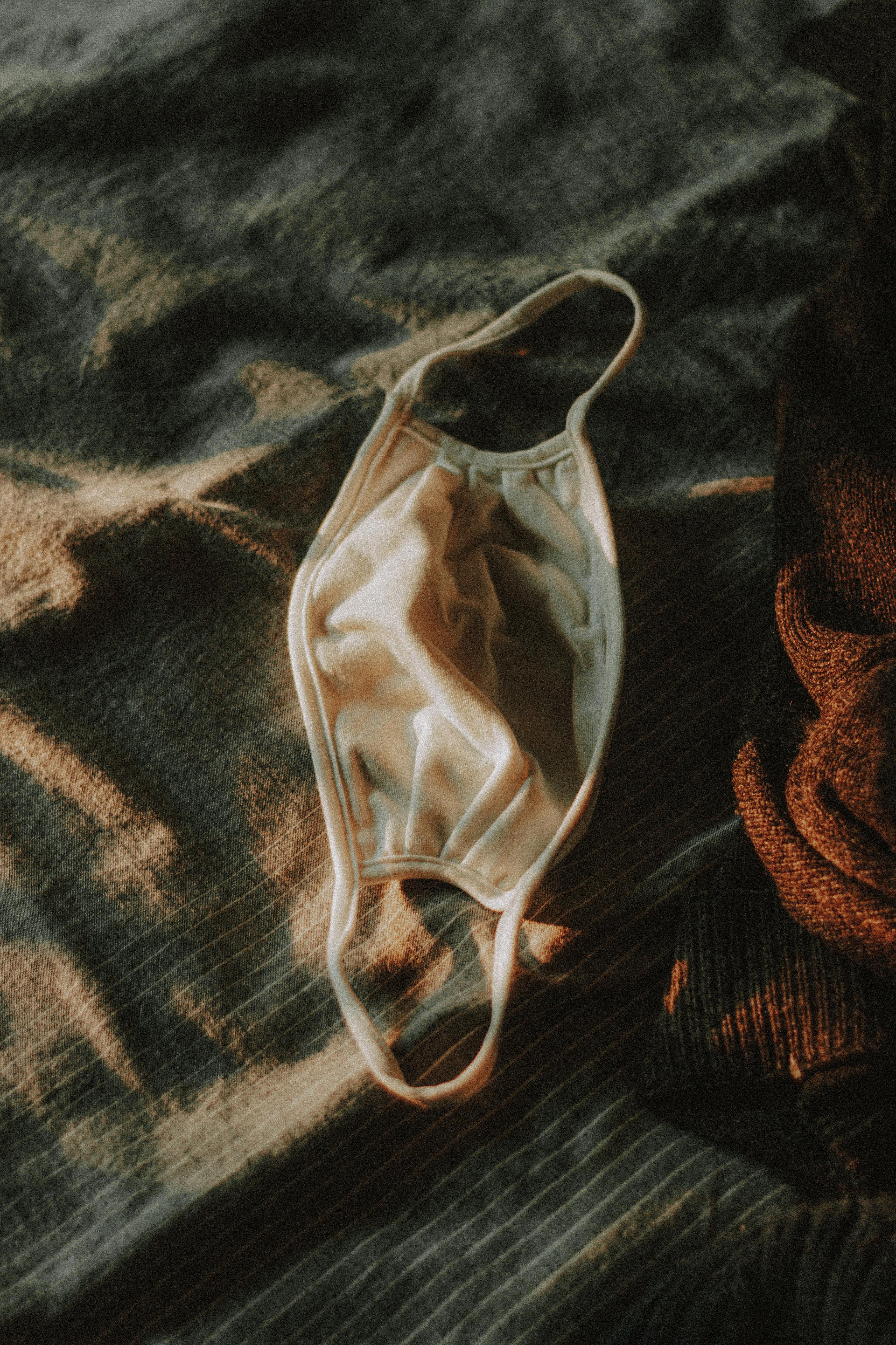Fabric mask on crumpled textile in sunbeam · Free Stock Photo