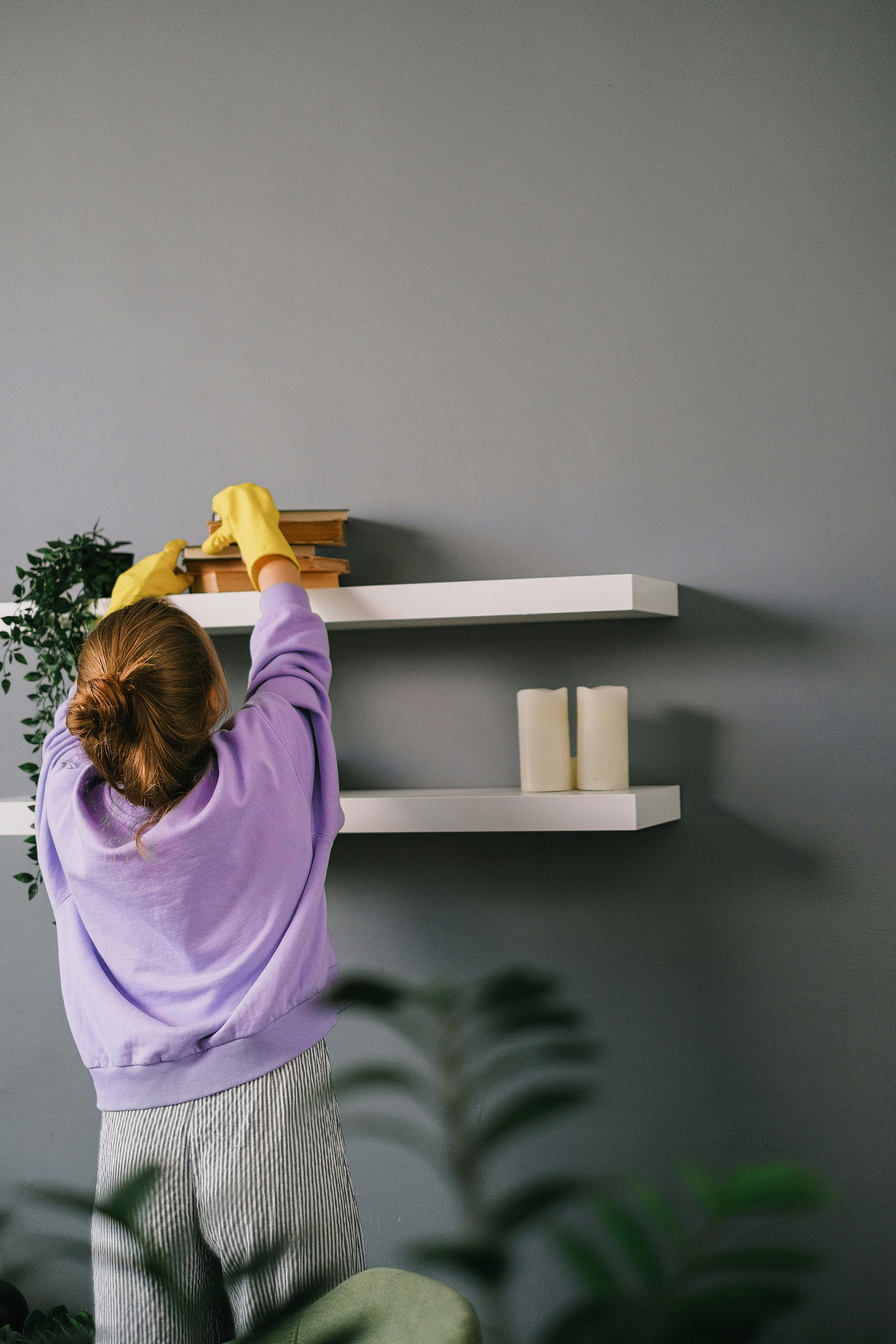 Woman taking books while cleaning shelves in room · Free Stock Photo