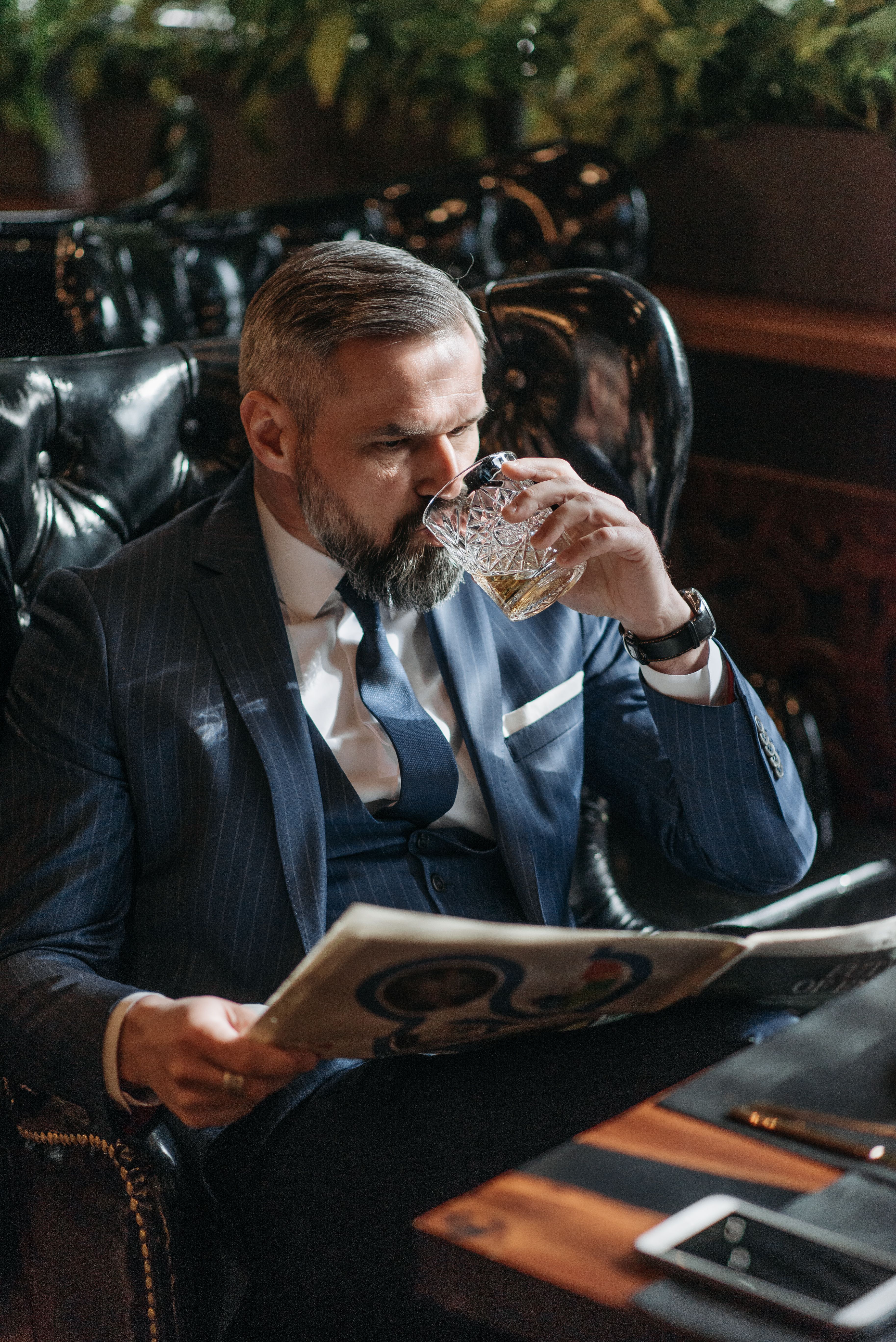 A Man Drinking While Reading the Newspaper · Free Stock Photo