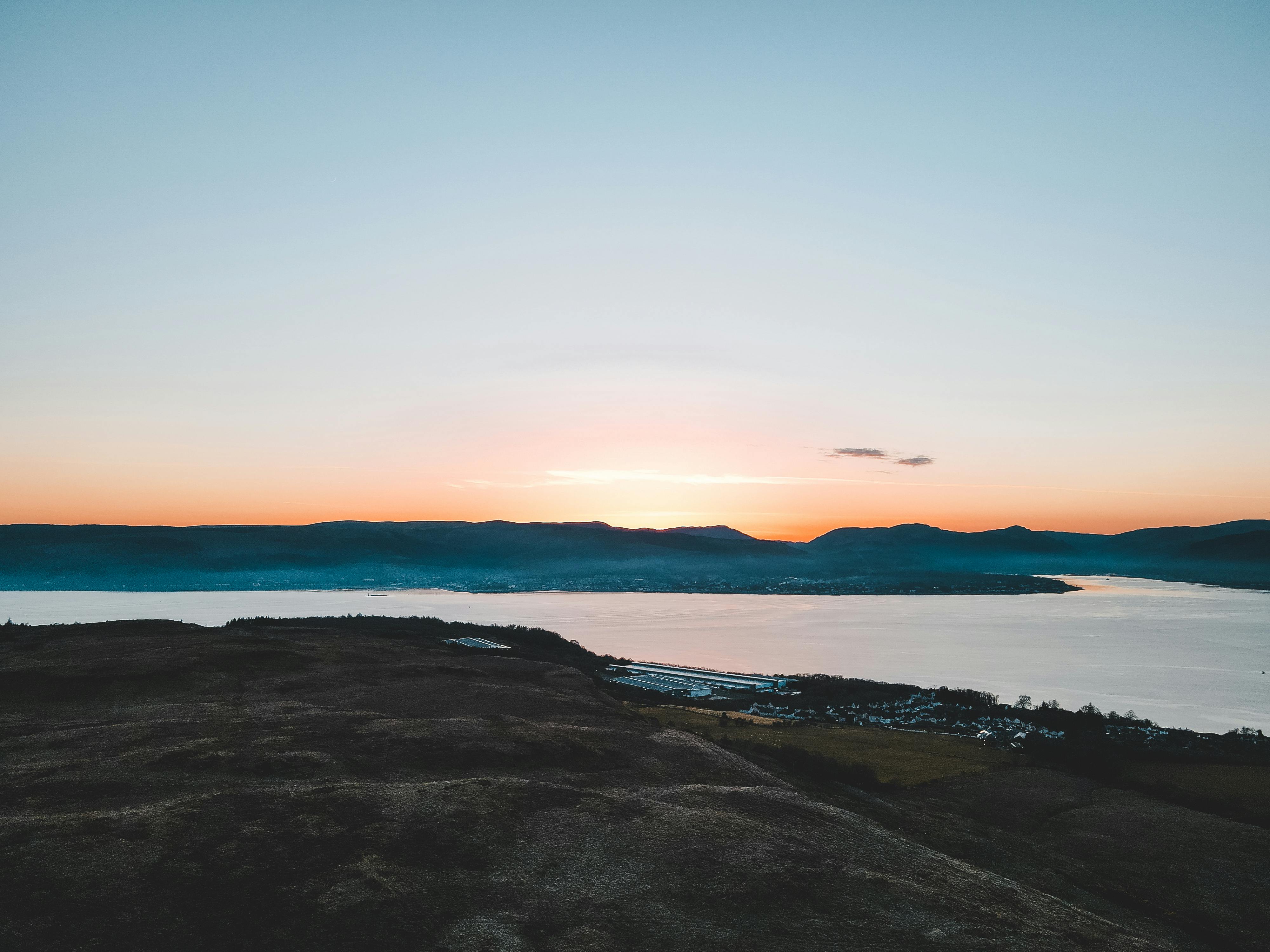Sun Setting Over Coastal Hills · Free Stock Photo