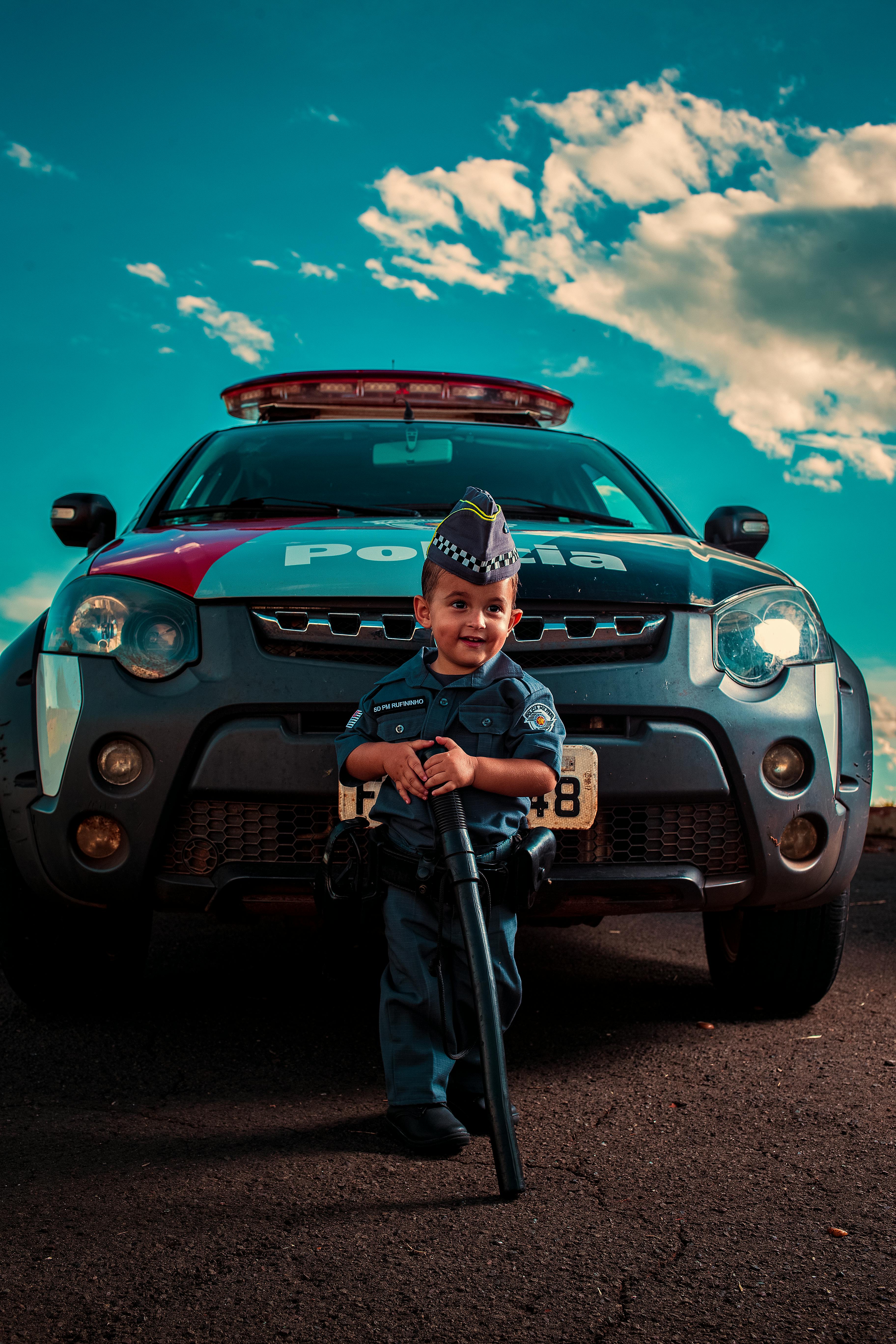 Boy Dressed as a Policeman Posing with a Police Car against Turquoise ...