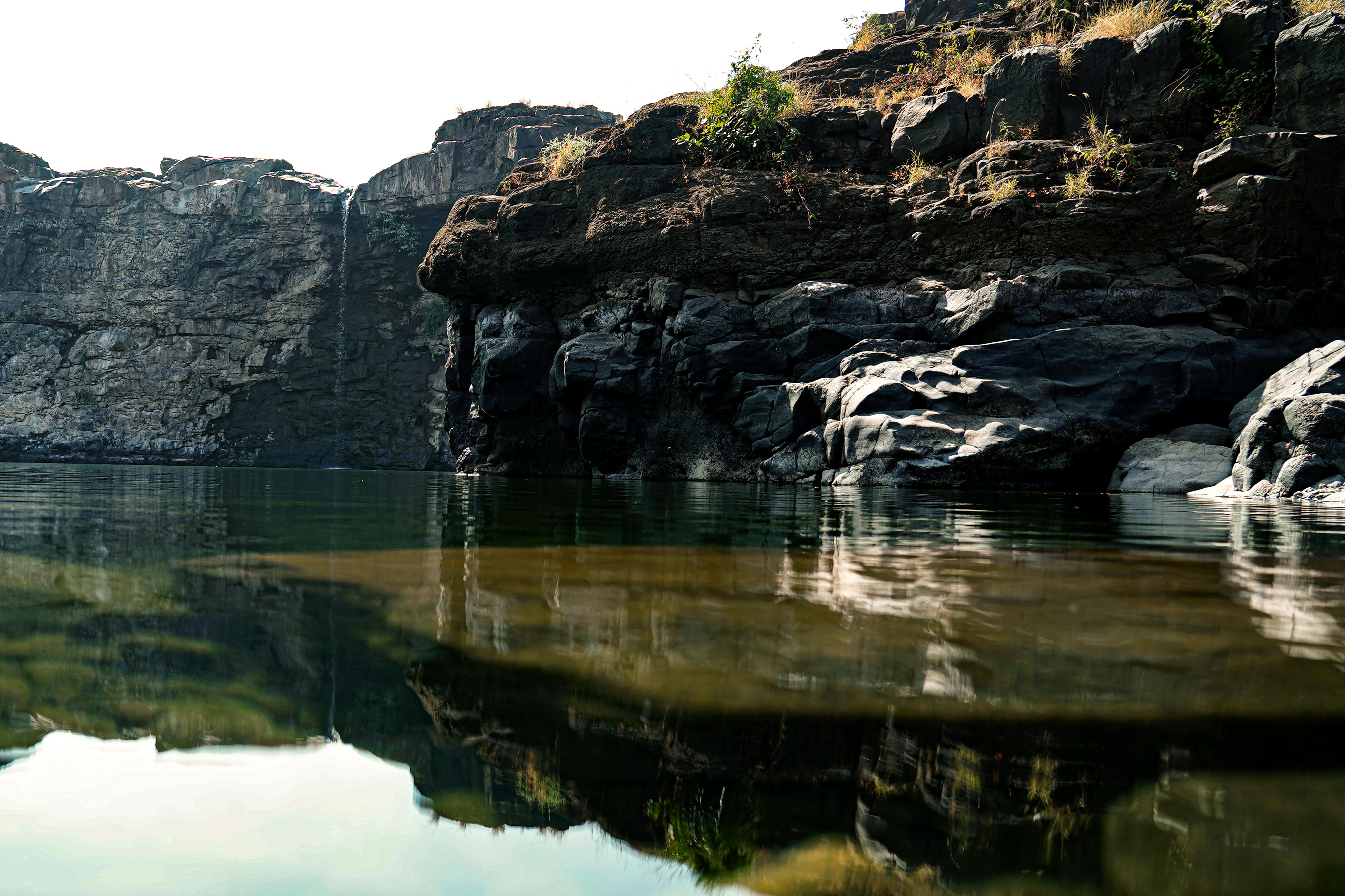 Reflection of Black Rock Formations on the Body of Water · Free Stock Photo