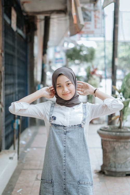 Girl In White Long Sleeve Shirt And Blue Denim Skirt Standing On Gray