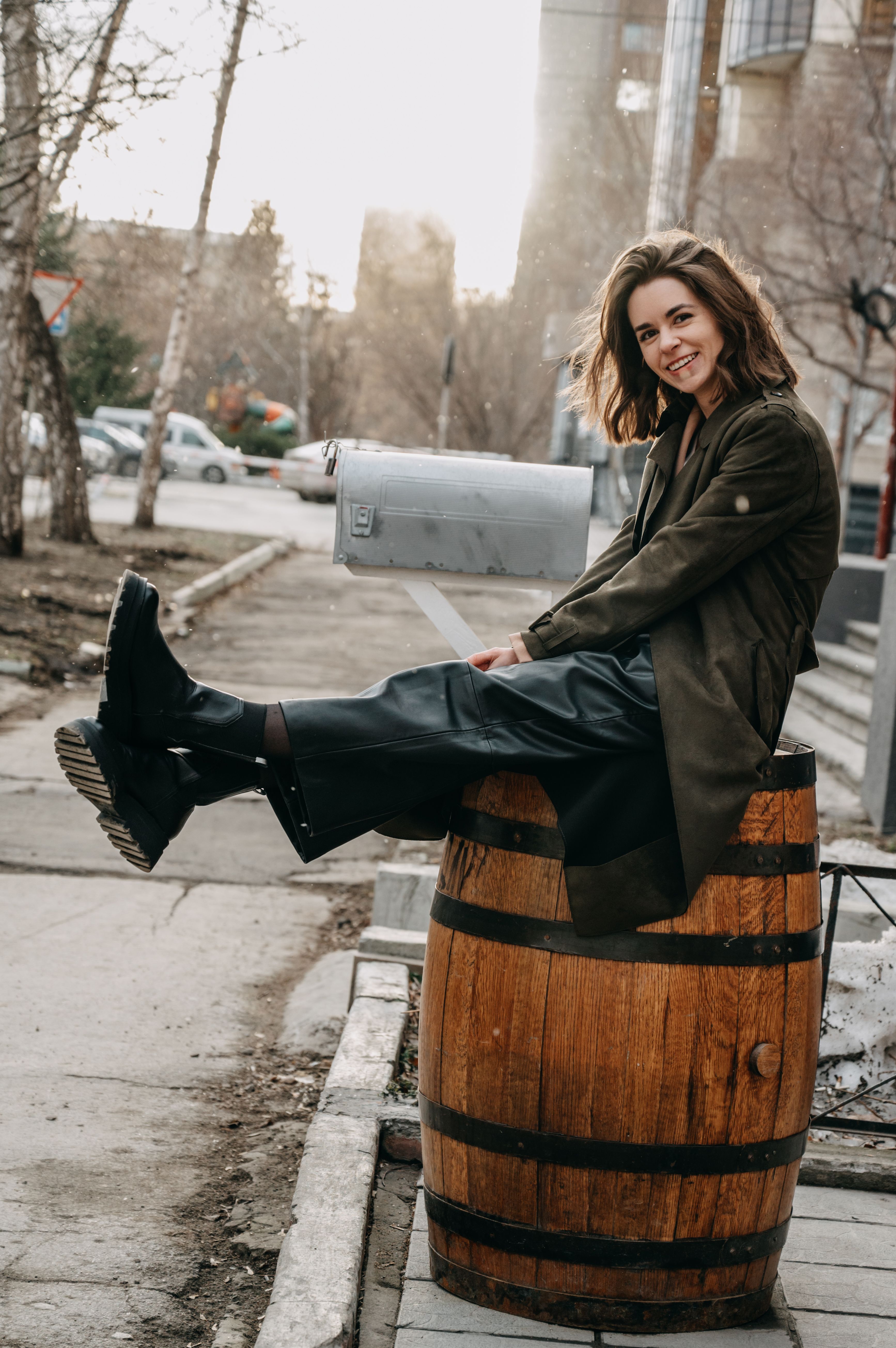 Smiling female sitting on wooden barrel · Free Stock Photo