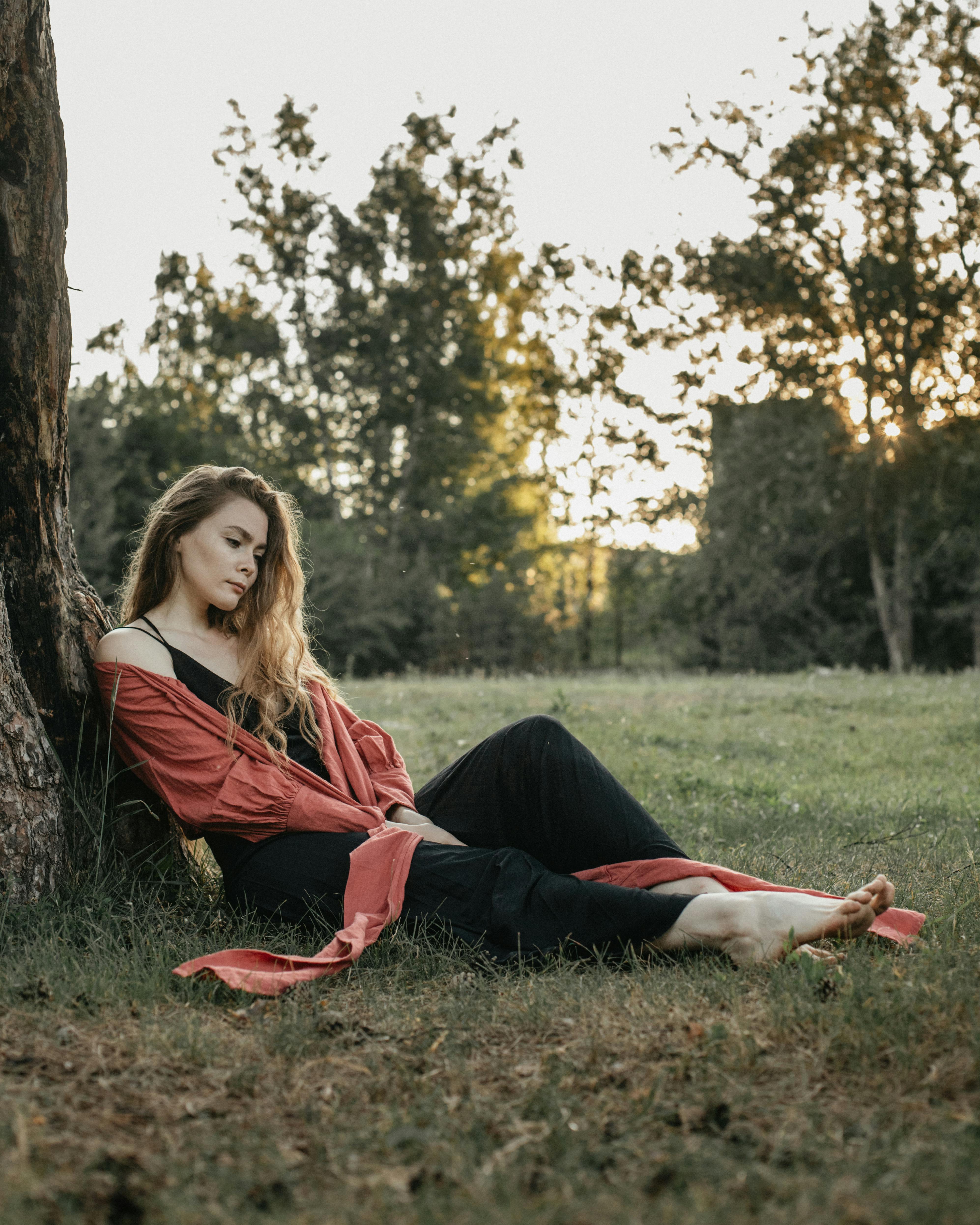 Woman sitting on ground leaning on tree · Free Stock Photo