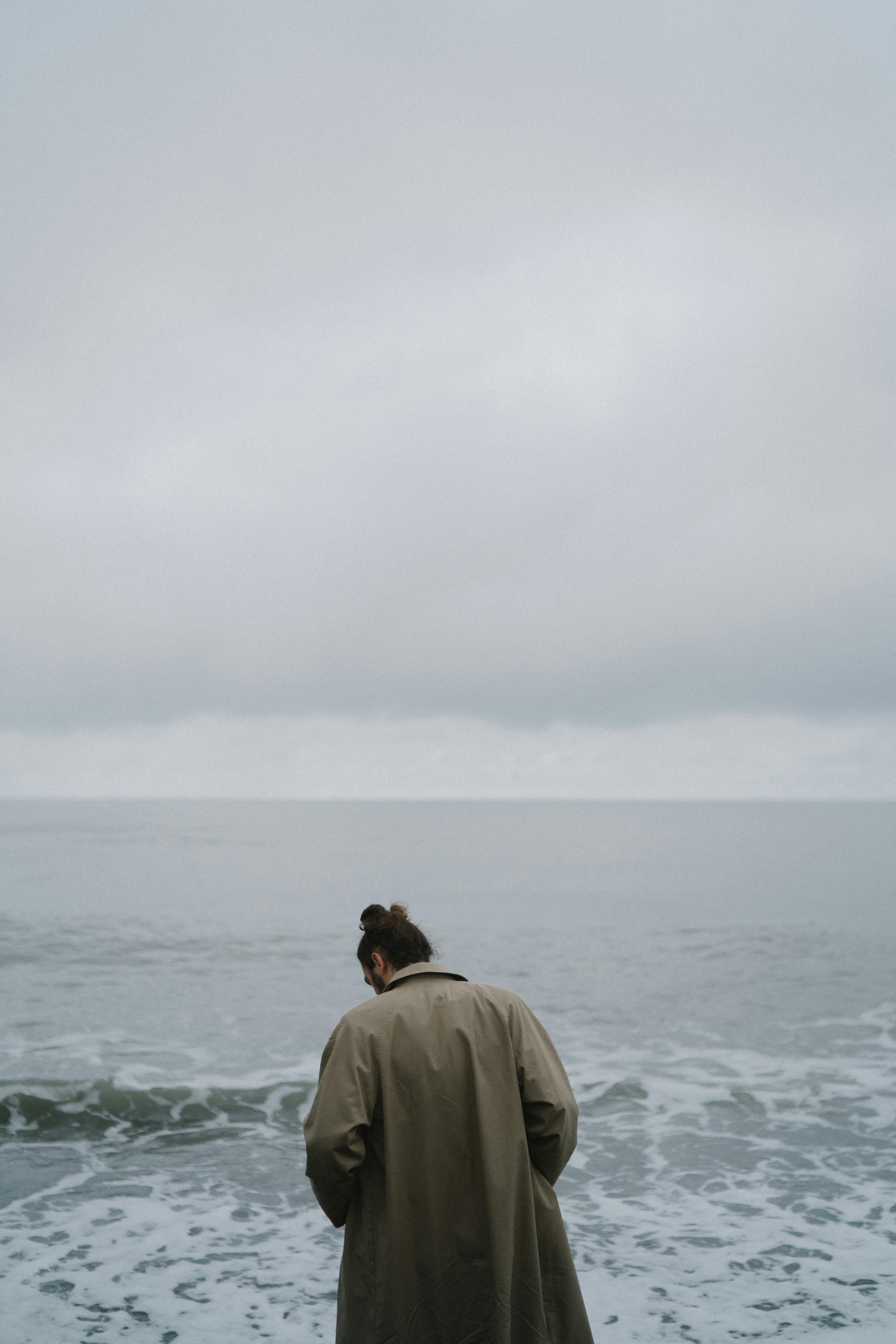 Stylish man model standing on sandy coast near sea · Free Stock Photo