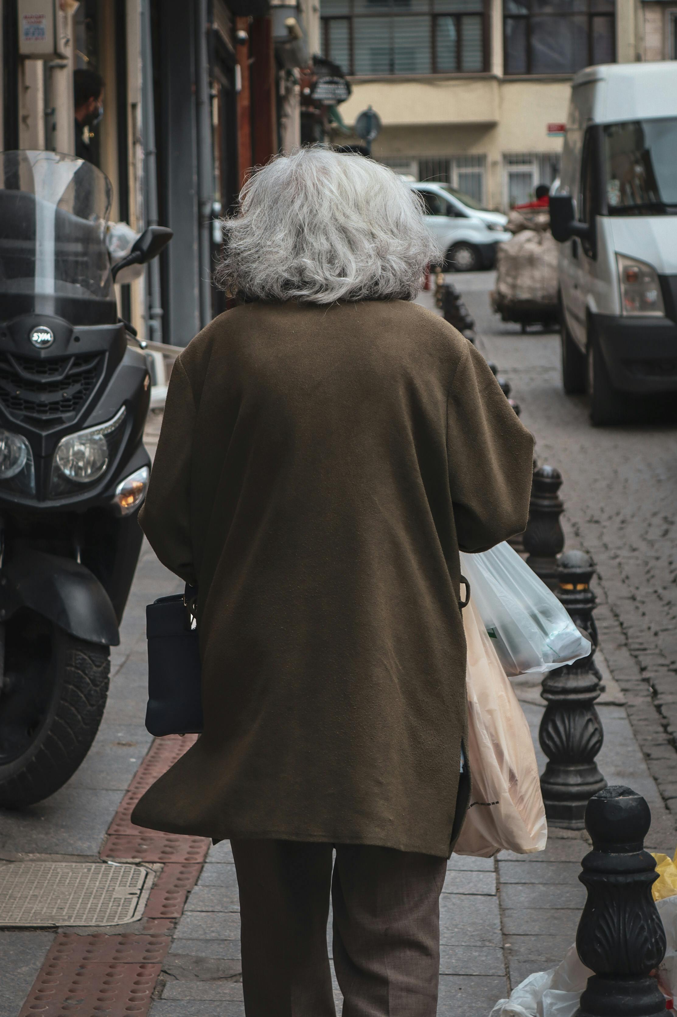 Back View of an Elderly Woman Walking on the Sidewalk · Free Stock Photo