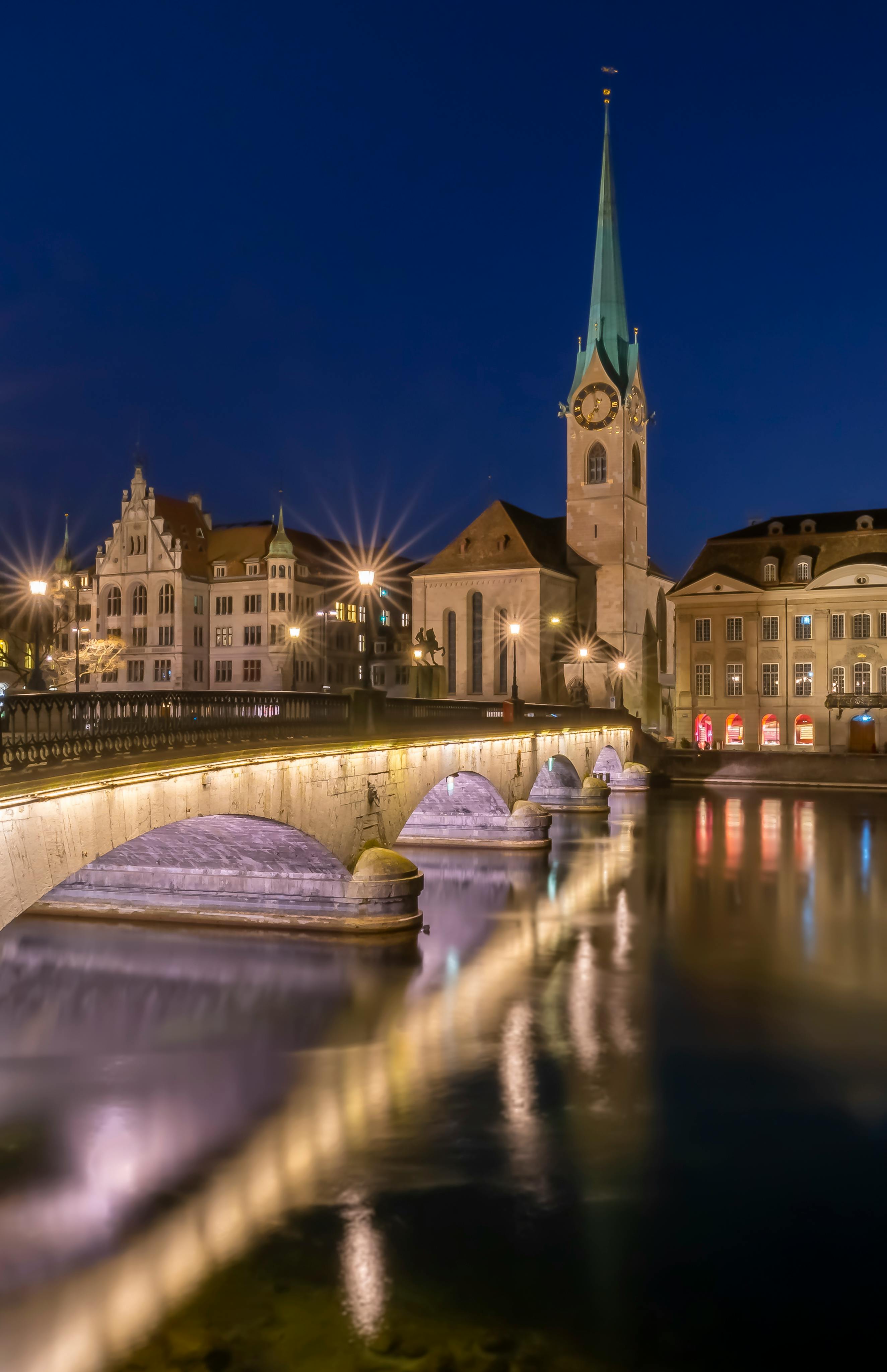 Brown Concrete Building Near Bridge during Night Time · Free Stock Photo
