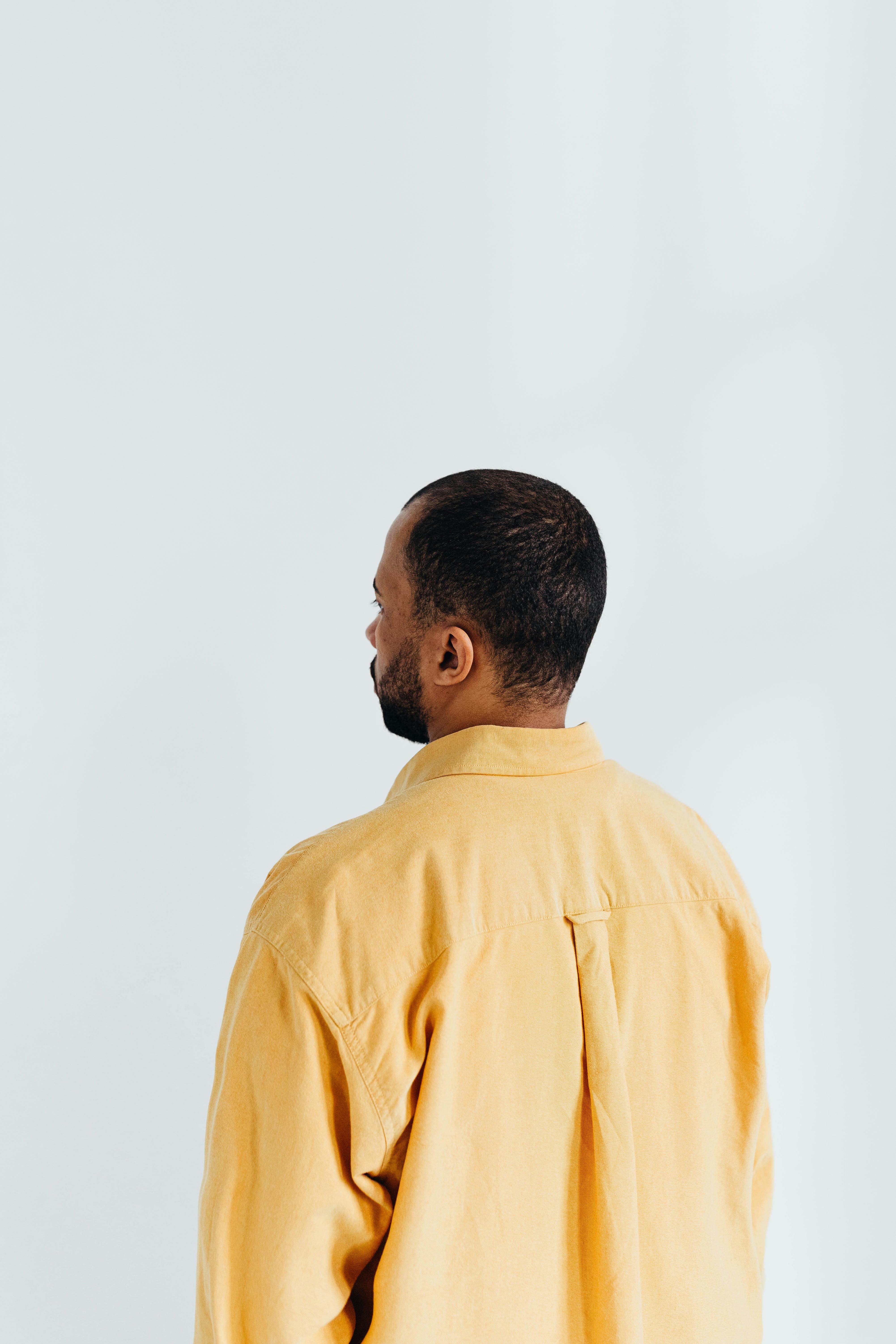 Man in Yellow Dress Shirt Standing beside White Wall · Free Stock Photo