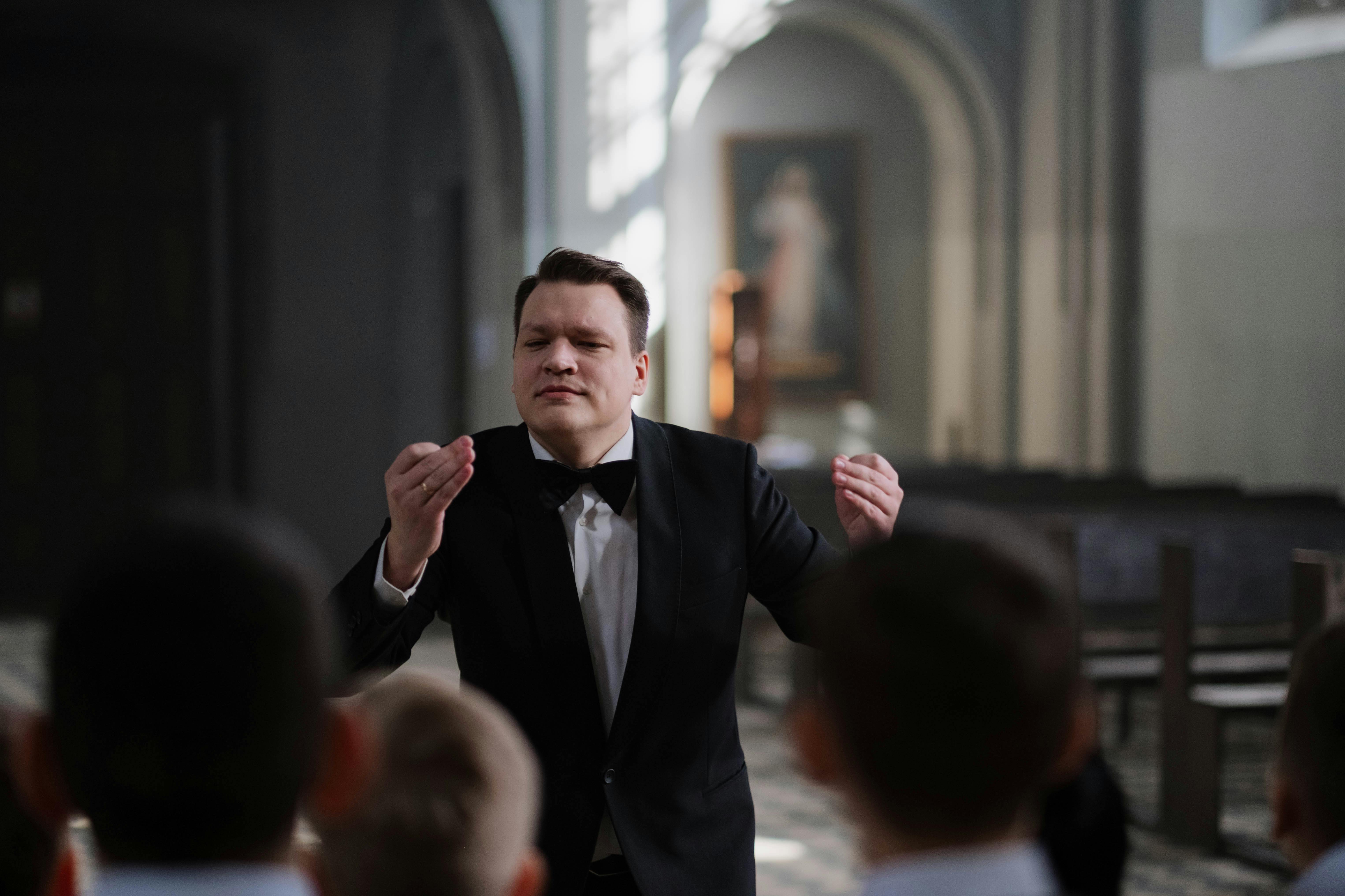 Choir Conductor in Black Suit Doing Hand Signal · Free Stock Photo