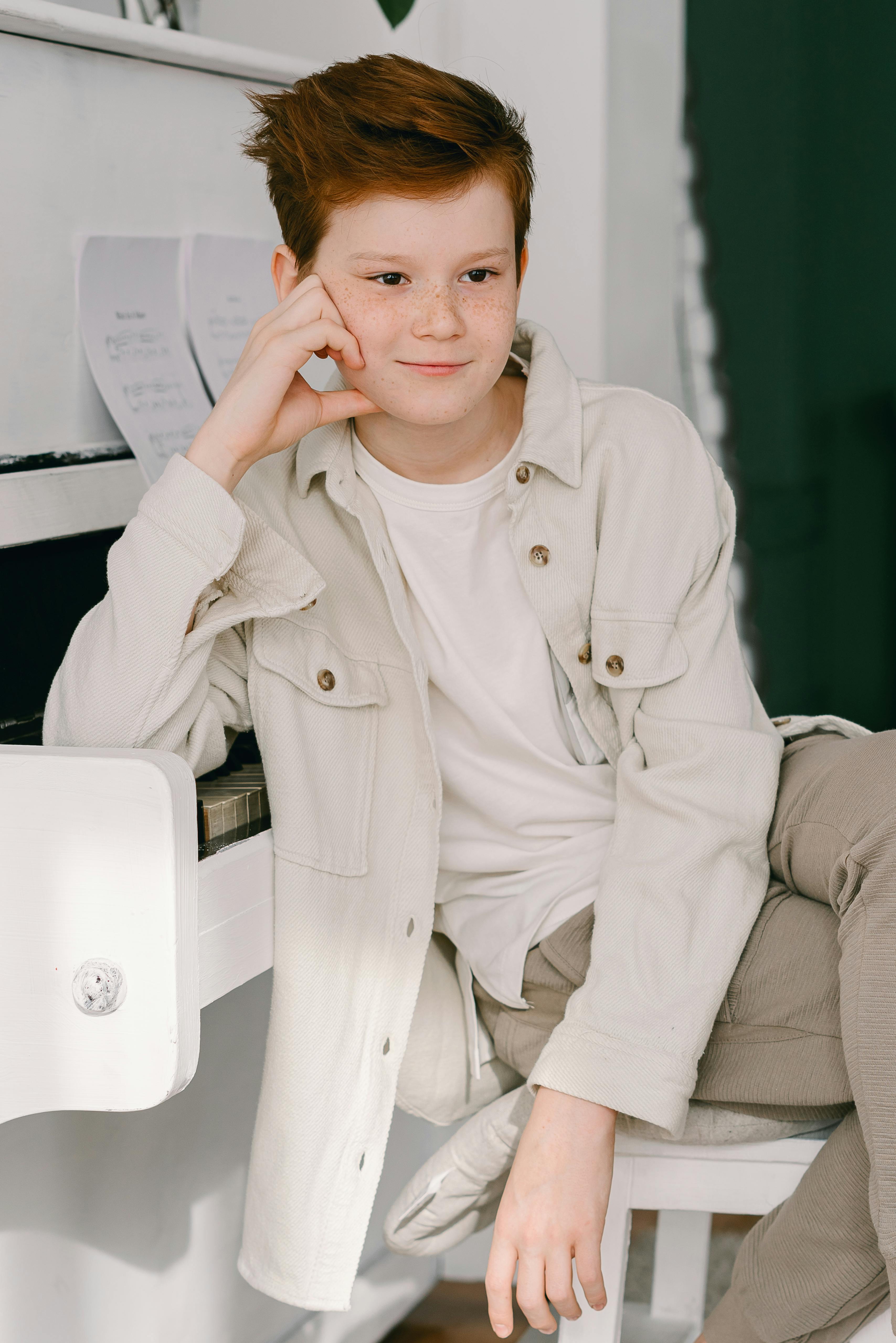 A Young Boy Sitting on a Chair · Free Stock Photo