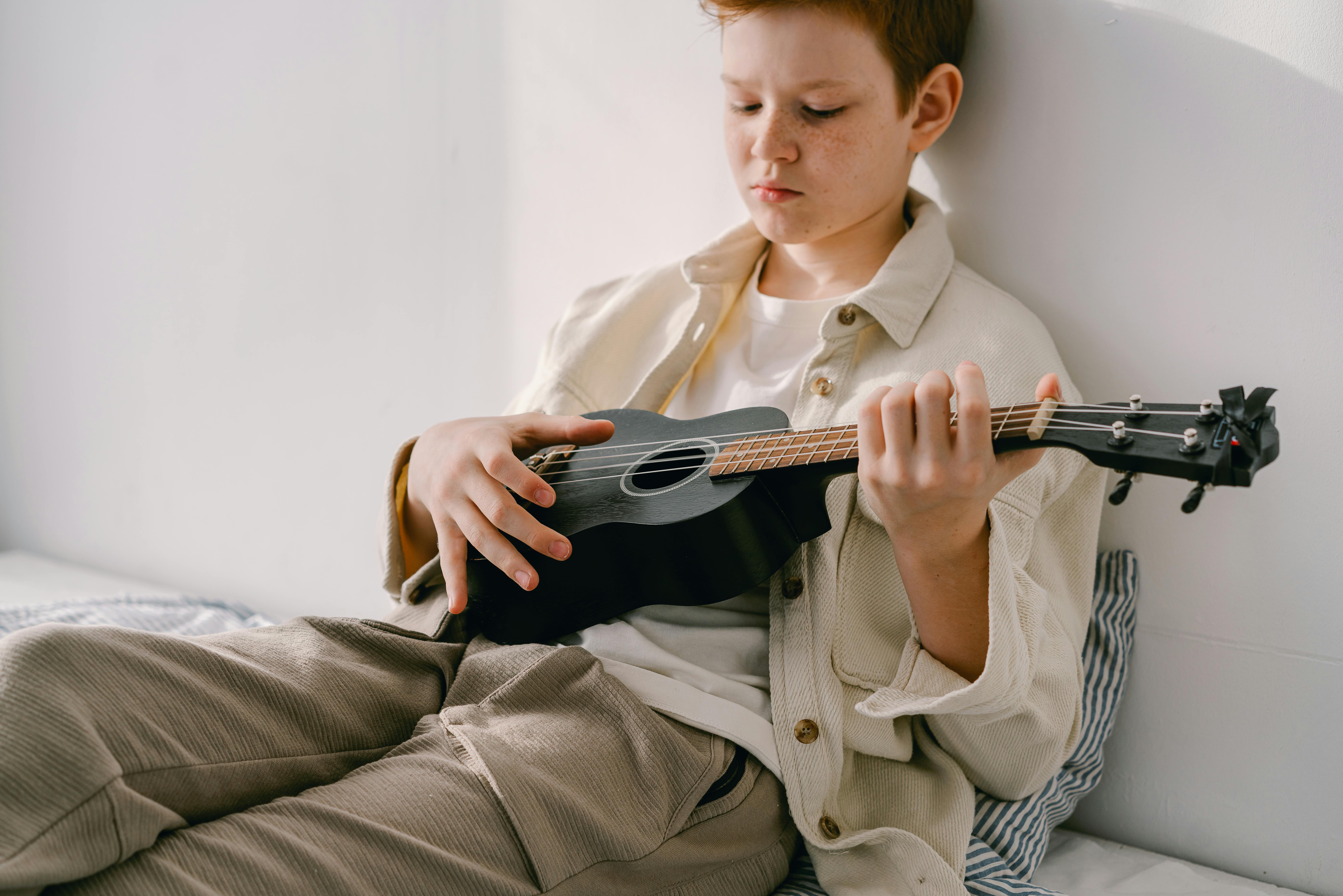 Close-up Photo of Boy Playing Ukulele · Free Stock Photo
