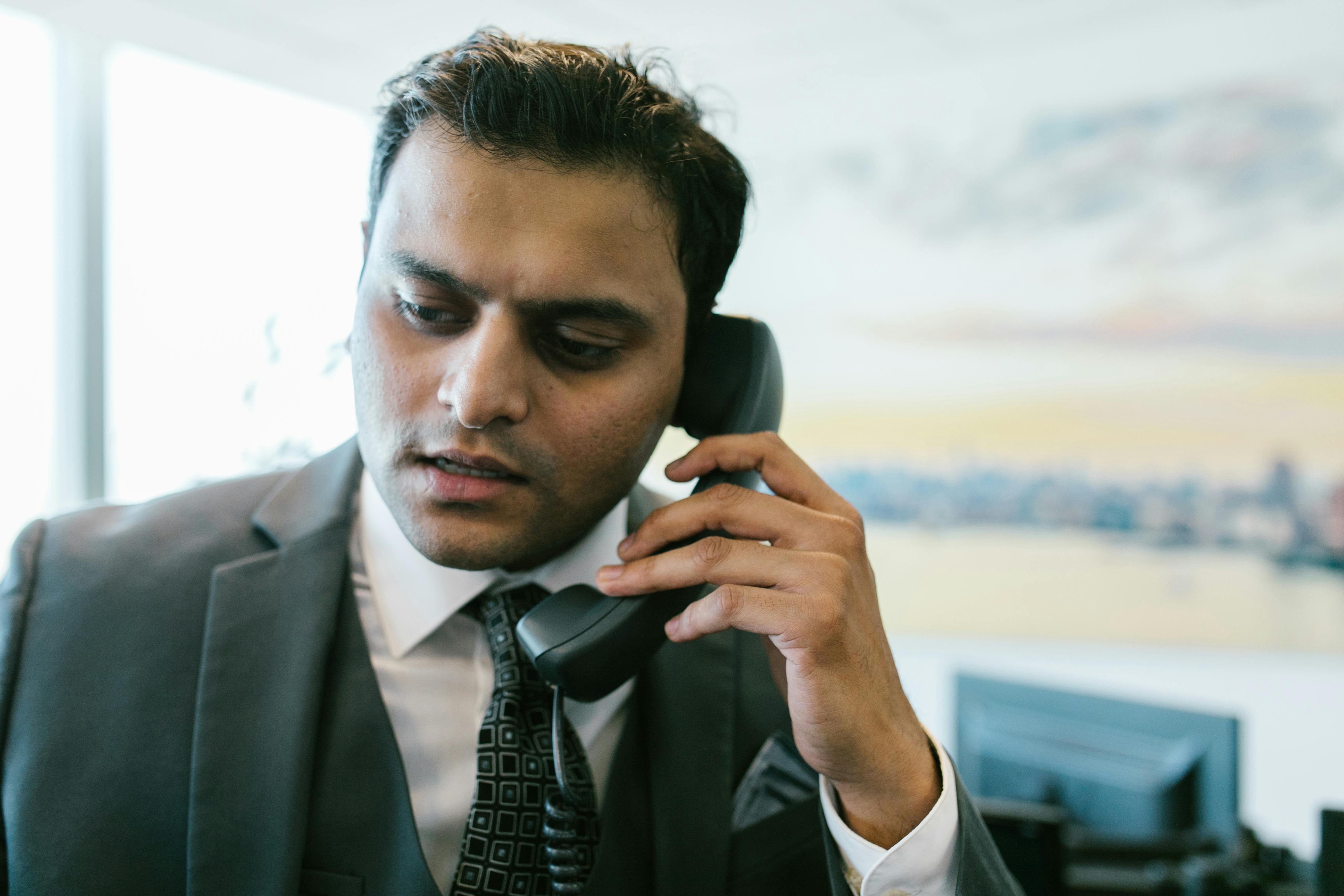 Man Wearing Brown Suit Jacket Mocking on White Telephone · Free Stock Photo