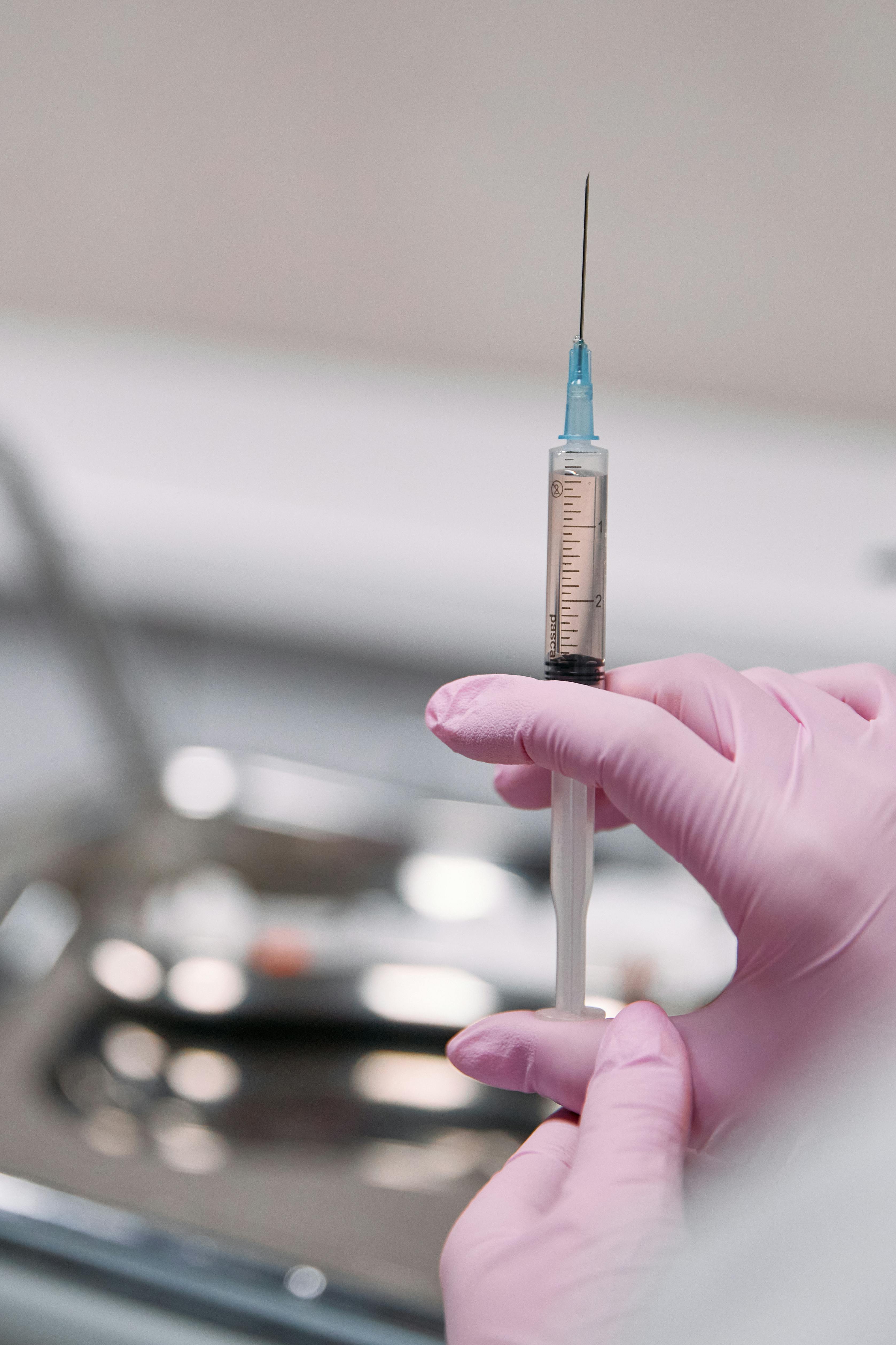 A Person Holding a Syringe with Needle · Free Stock Photo