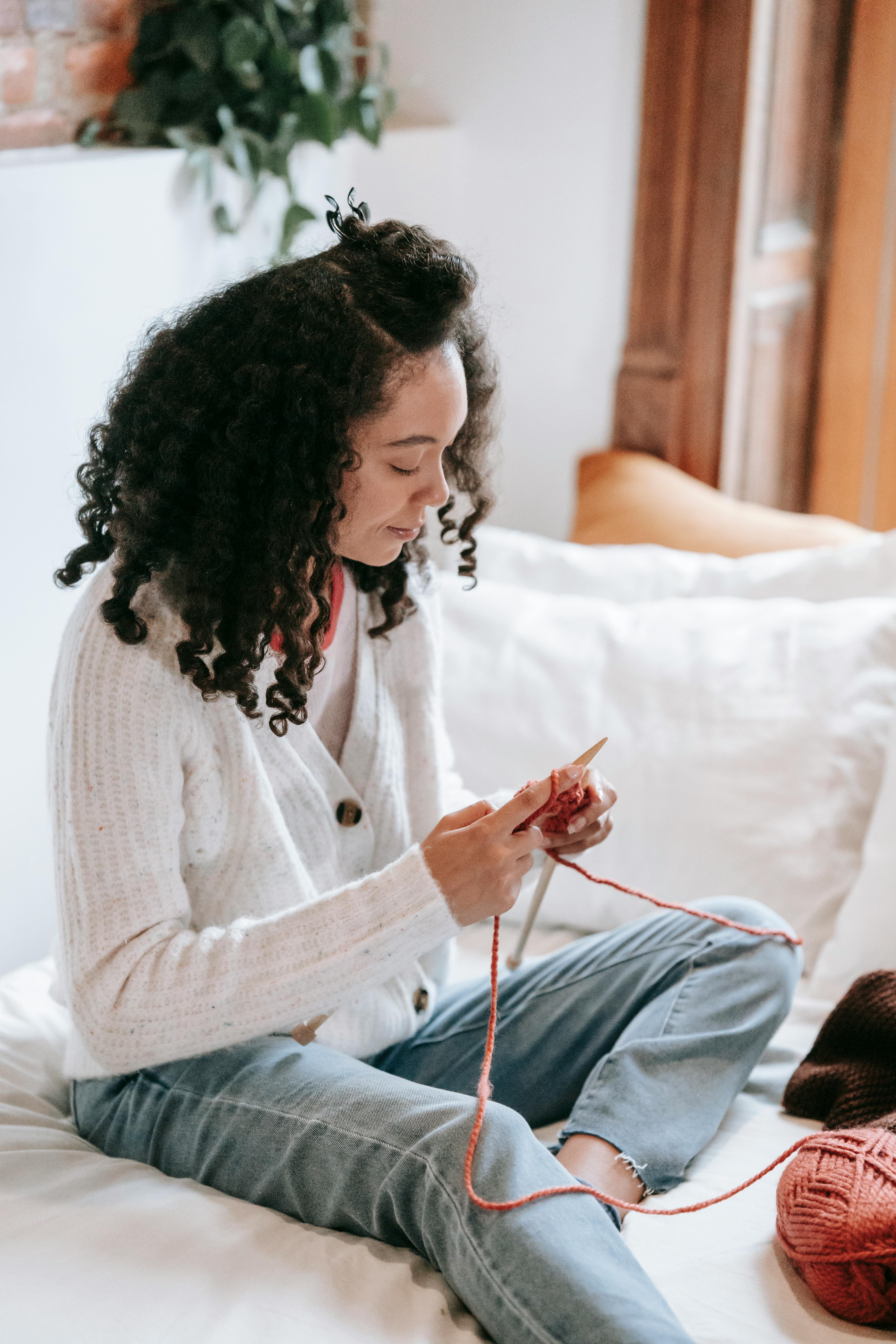 African American woman knitting with needles on bed · Free Stock Photo