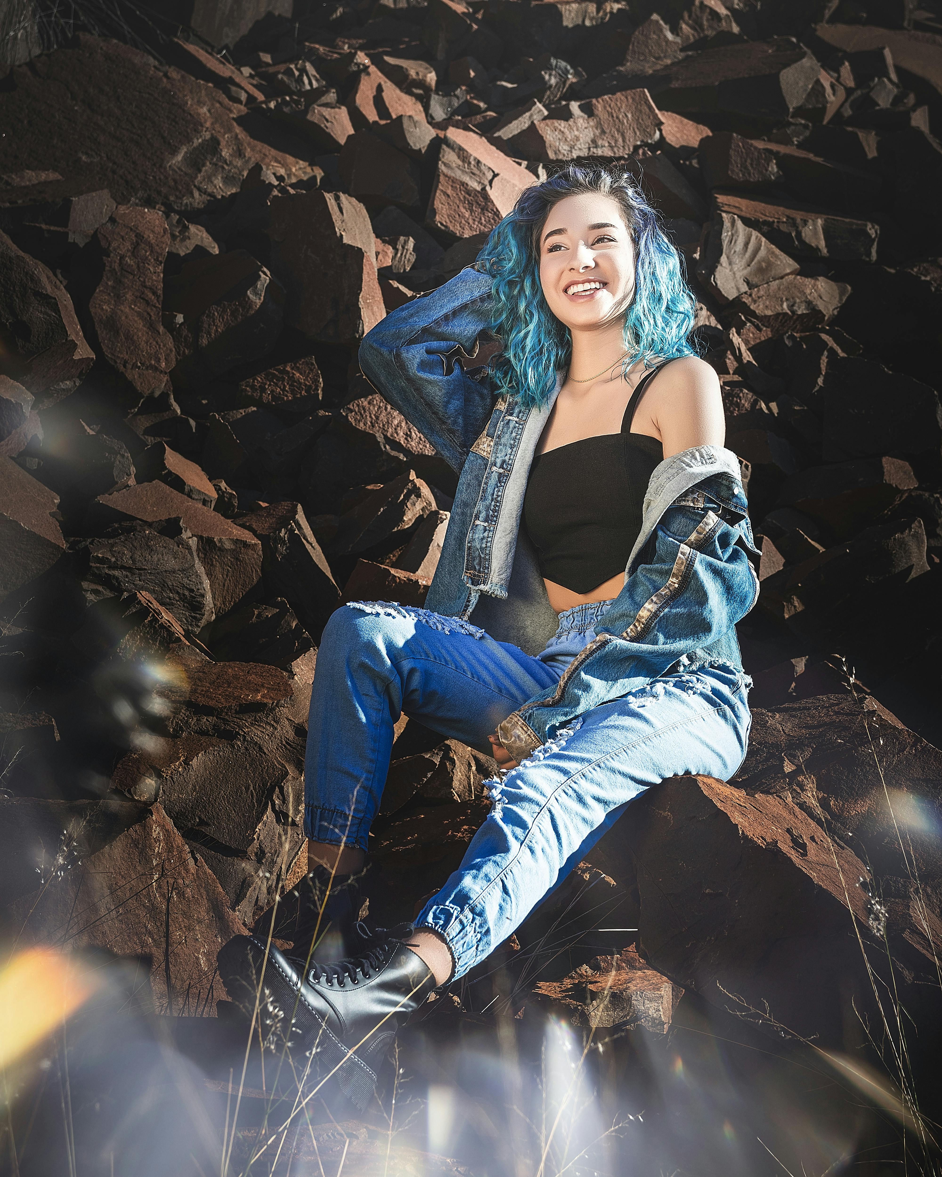 A Woman Smiling and Posing while Sitting on Rocks · Free Stock Photo