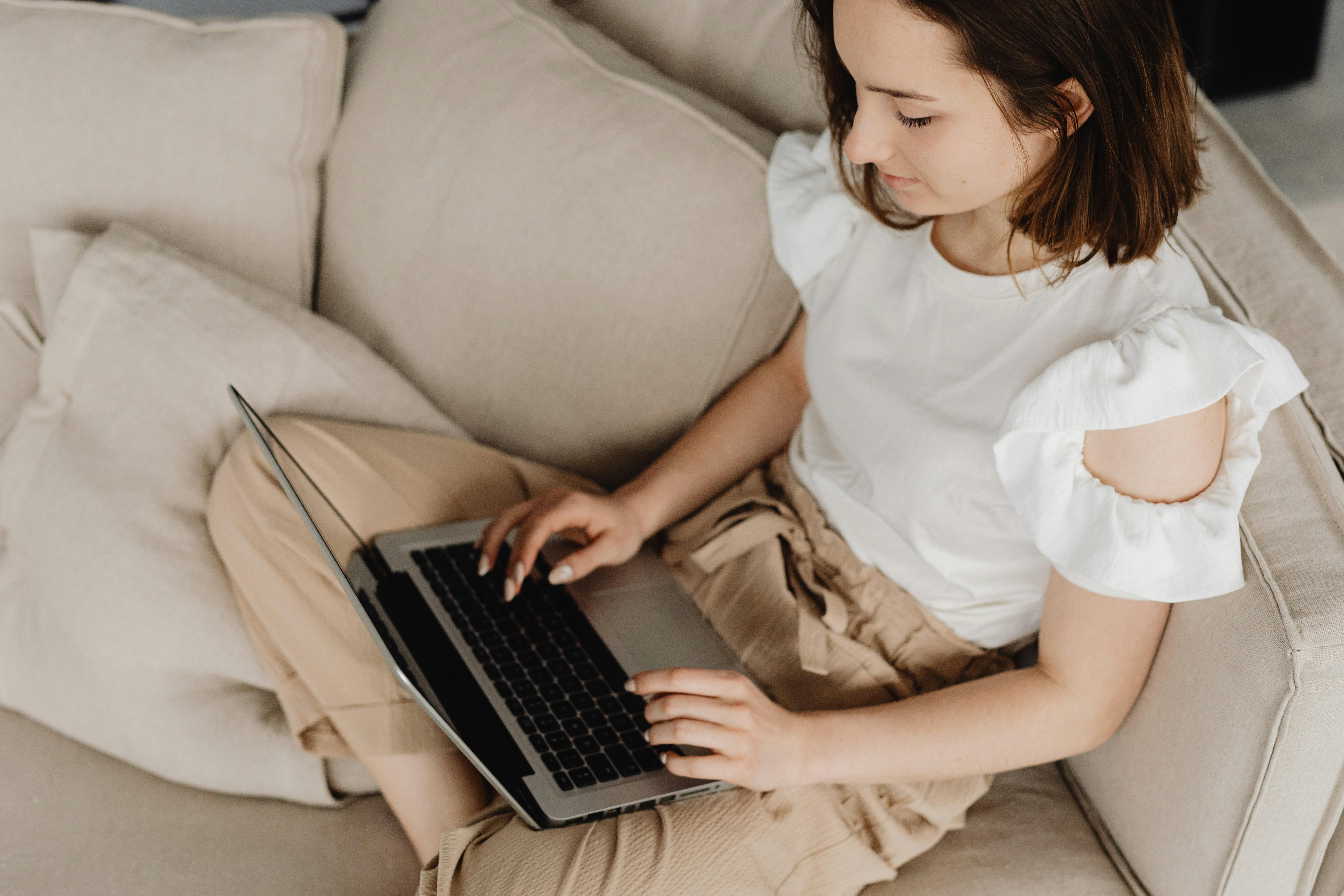 A Woman Typing on Laptop while Sitting on Couch · Free Stock Photo