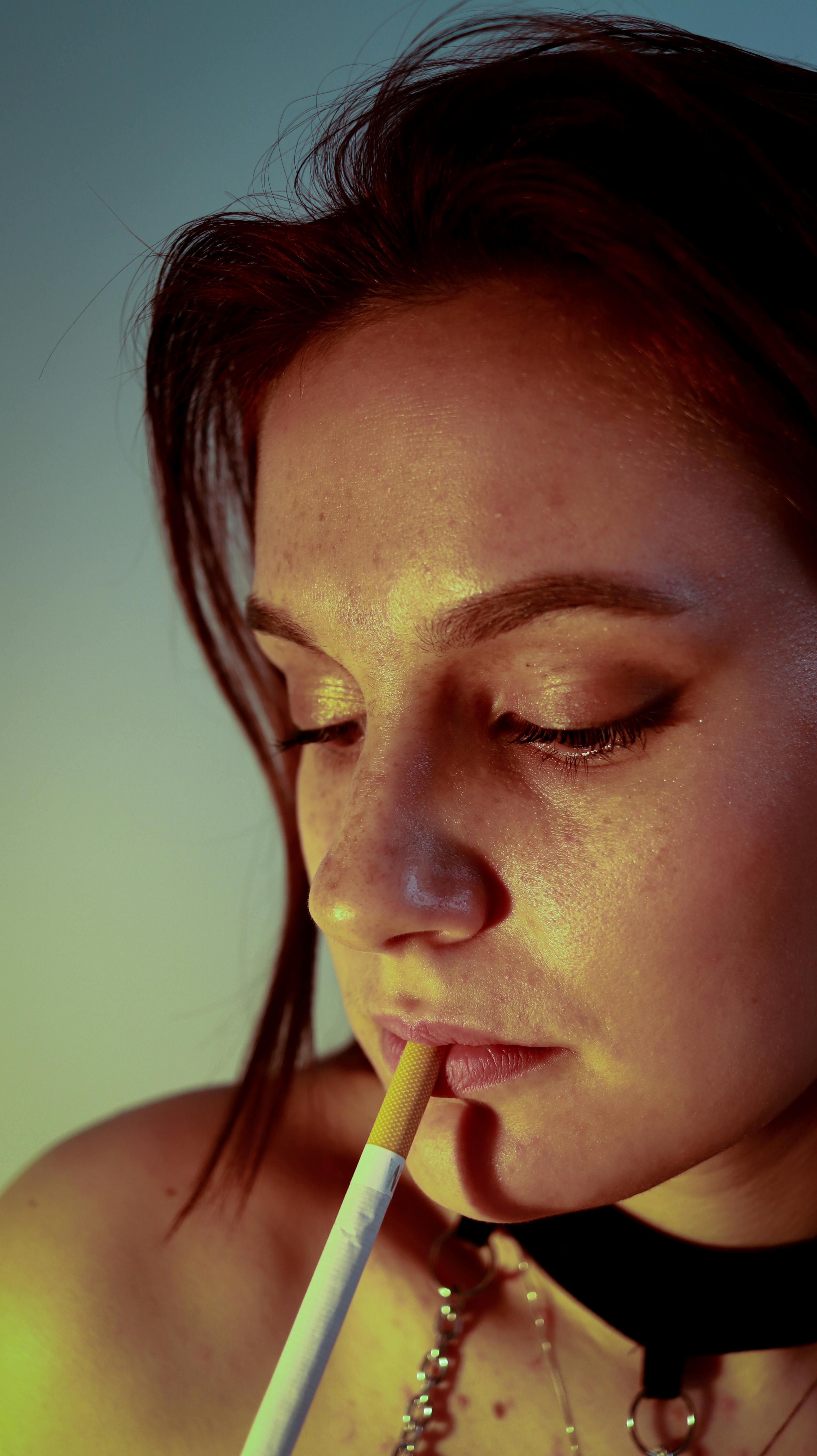 Woman Smoking Cigarette Near Brick Wall · Free Stock Photo