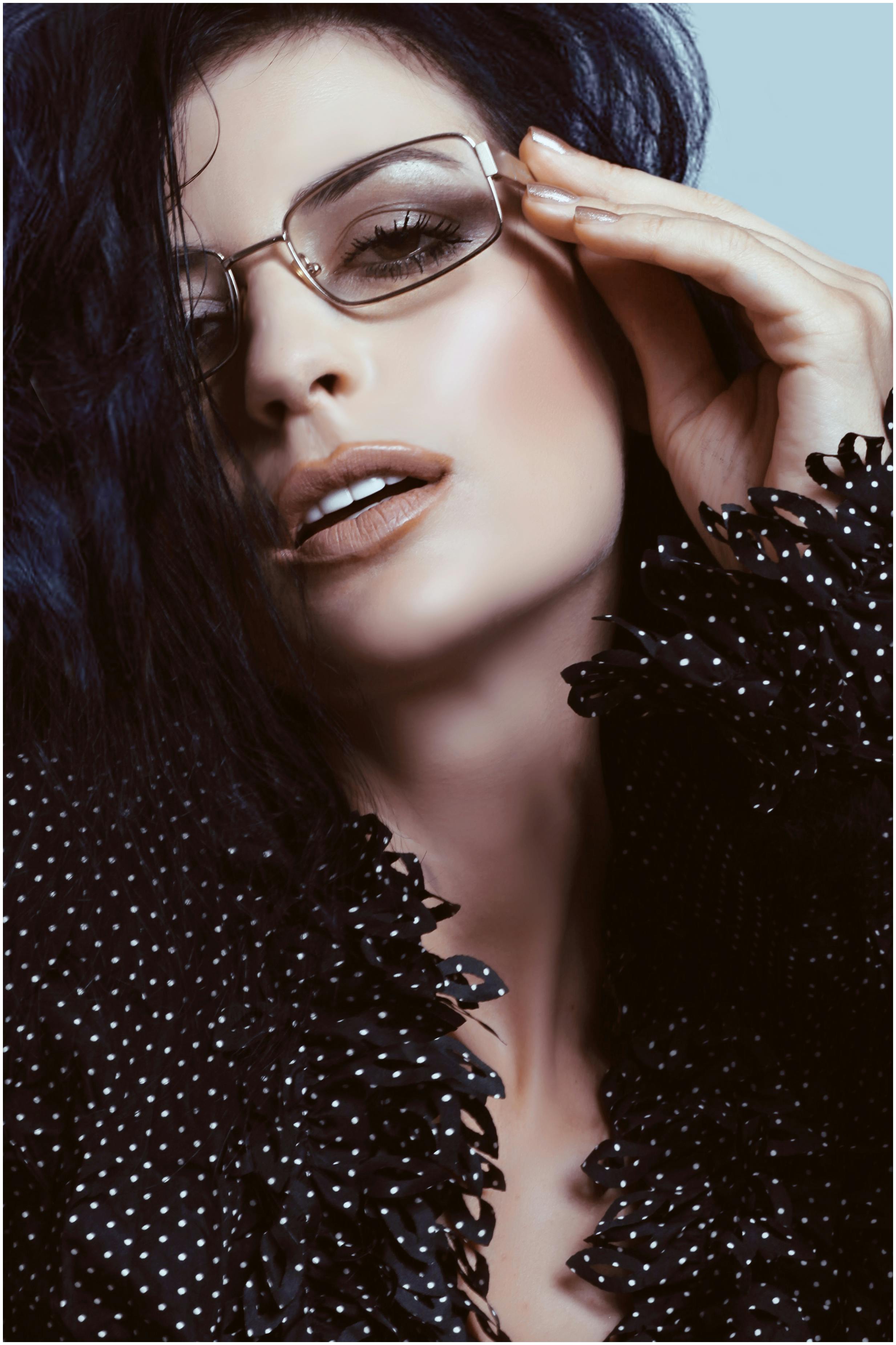 Stylish woman adjusting eyeglasses and looking at camera · Free Stock Photo