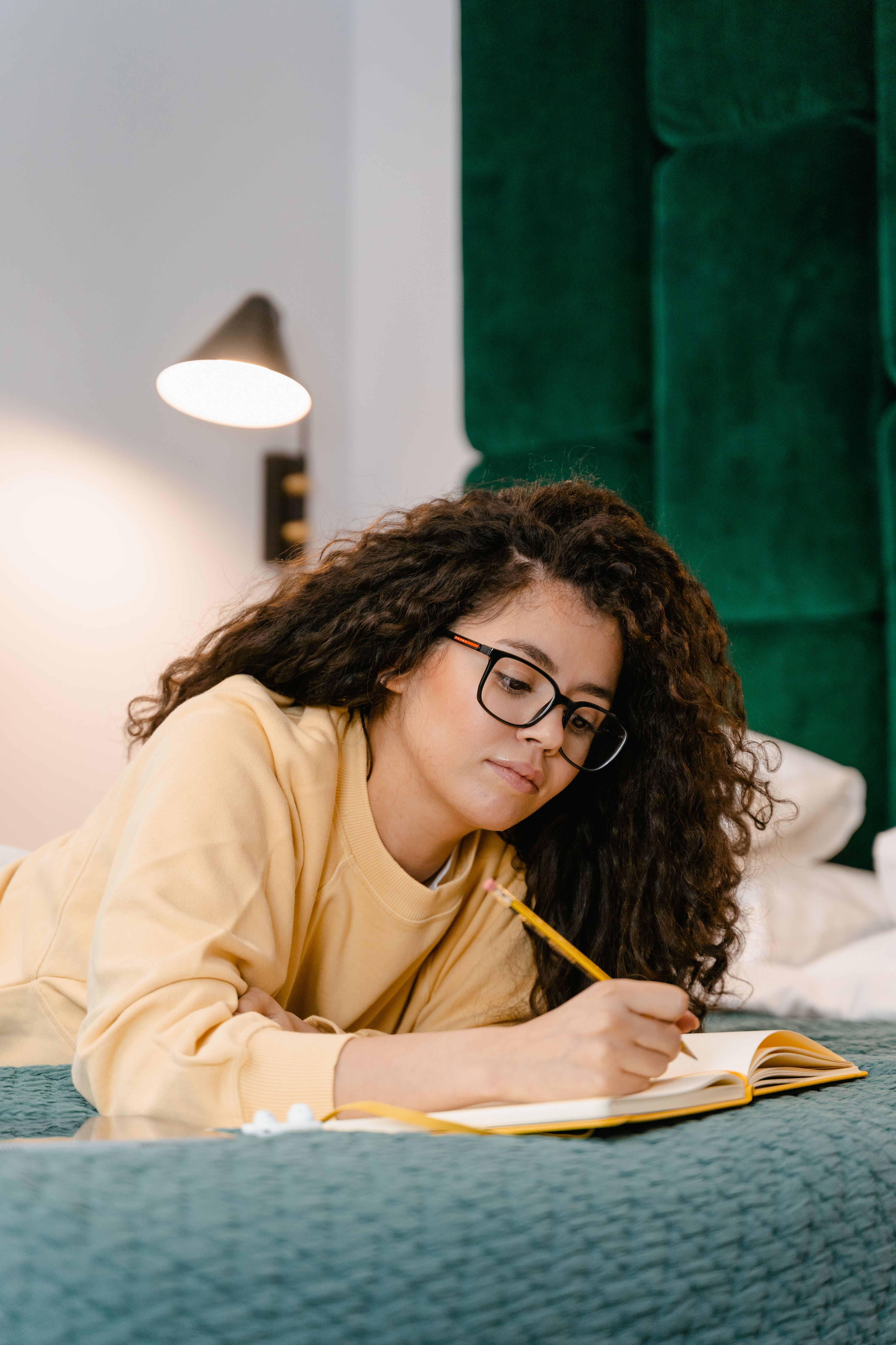 Woman Lying on Bed While Writing on a Notebook · Free Stock Photo