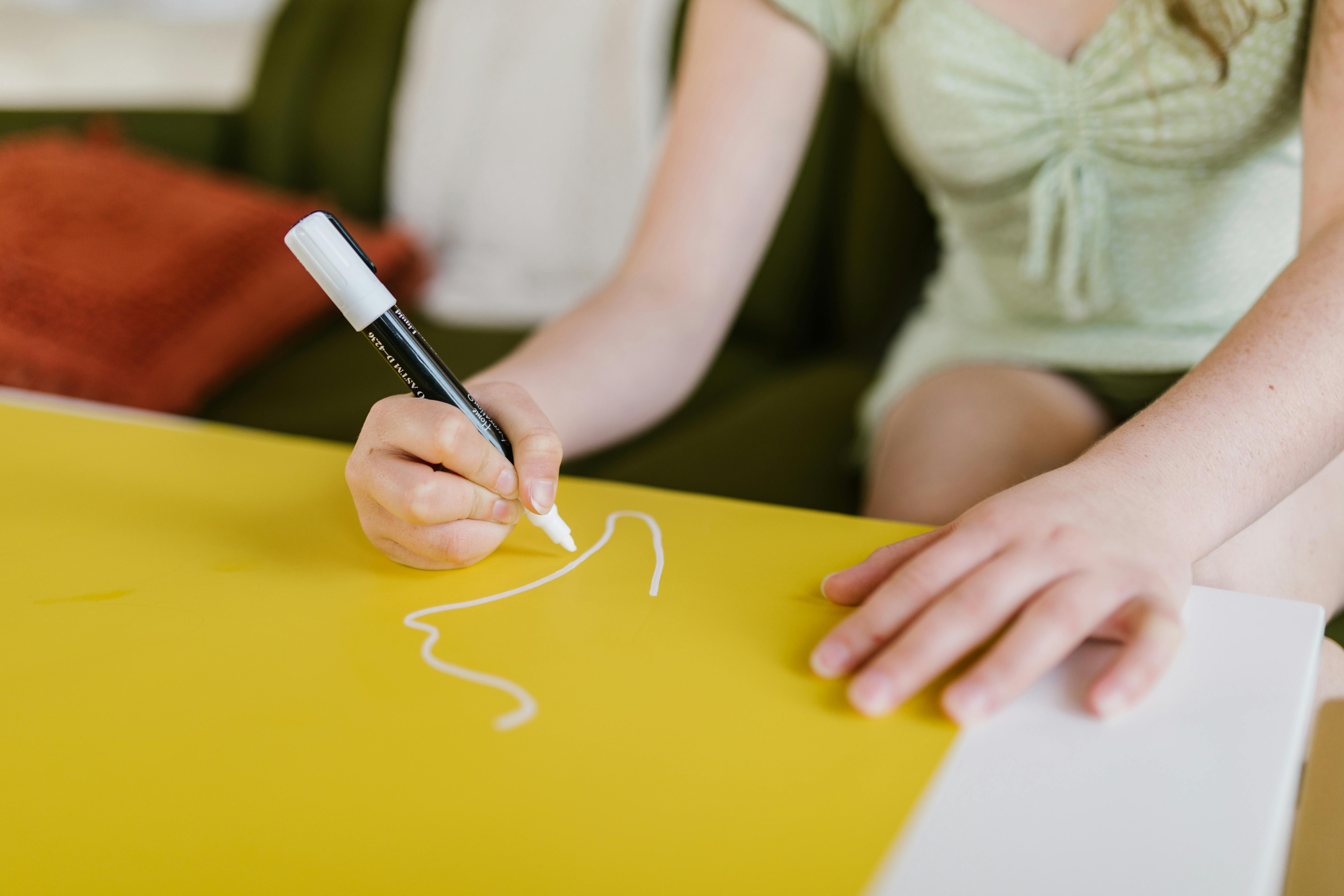 A Girl Drawing on a Yellow Paper · Free Stock Photo
