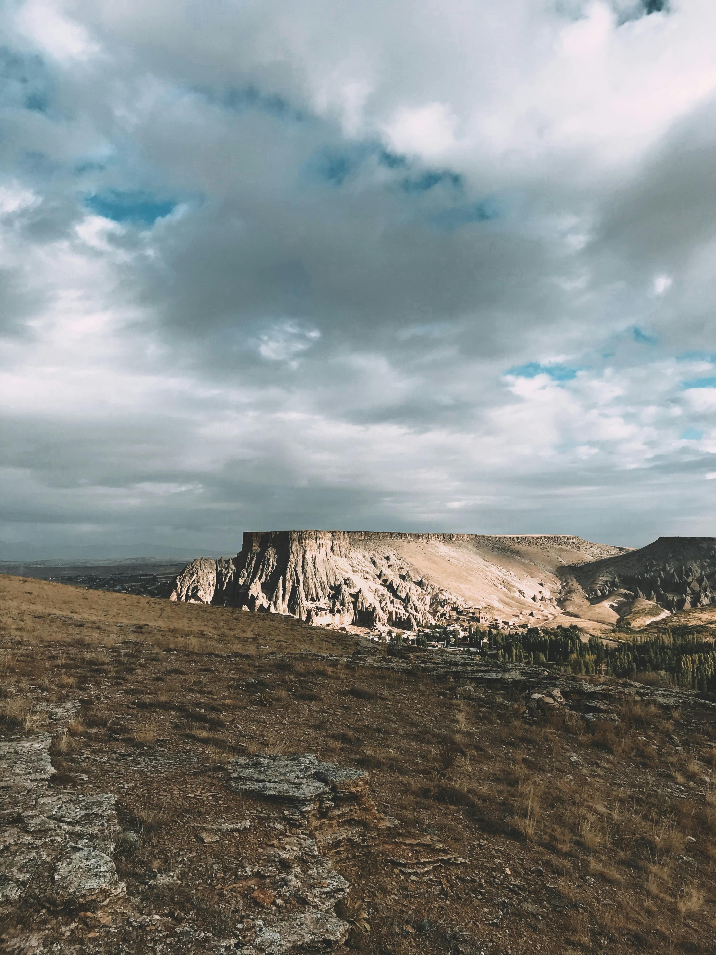 Hilly area against rocky formation · Free Stock Photo
