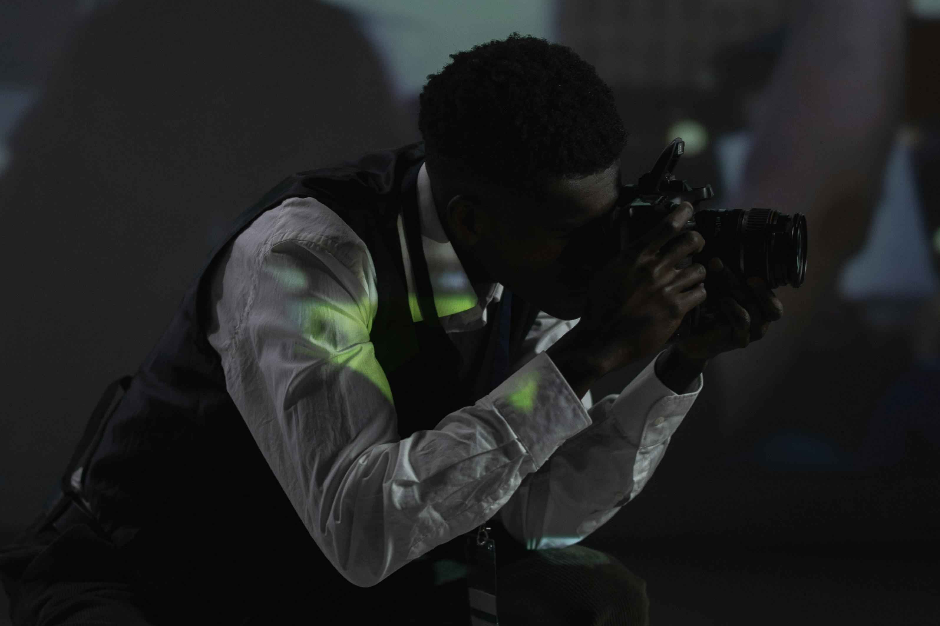 A Man in Black Vest Taking Photos Using a DSLR Camera · Free Stock Photo