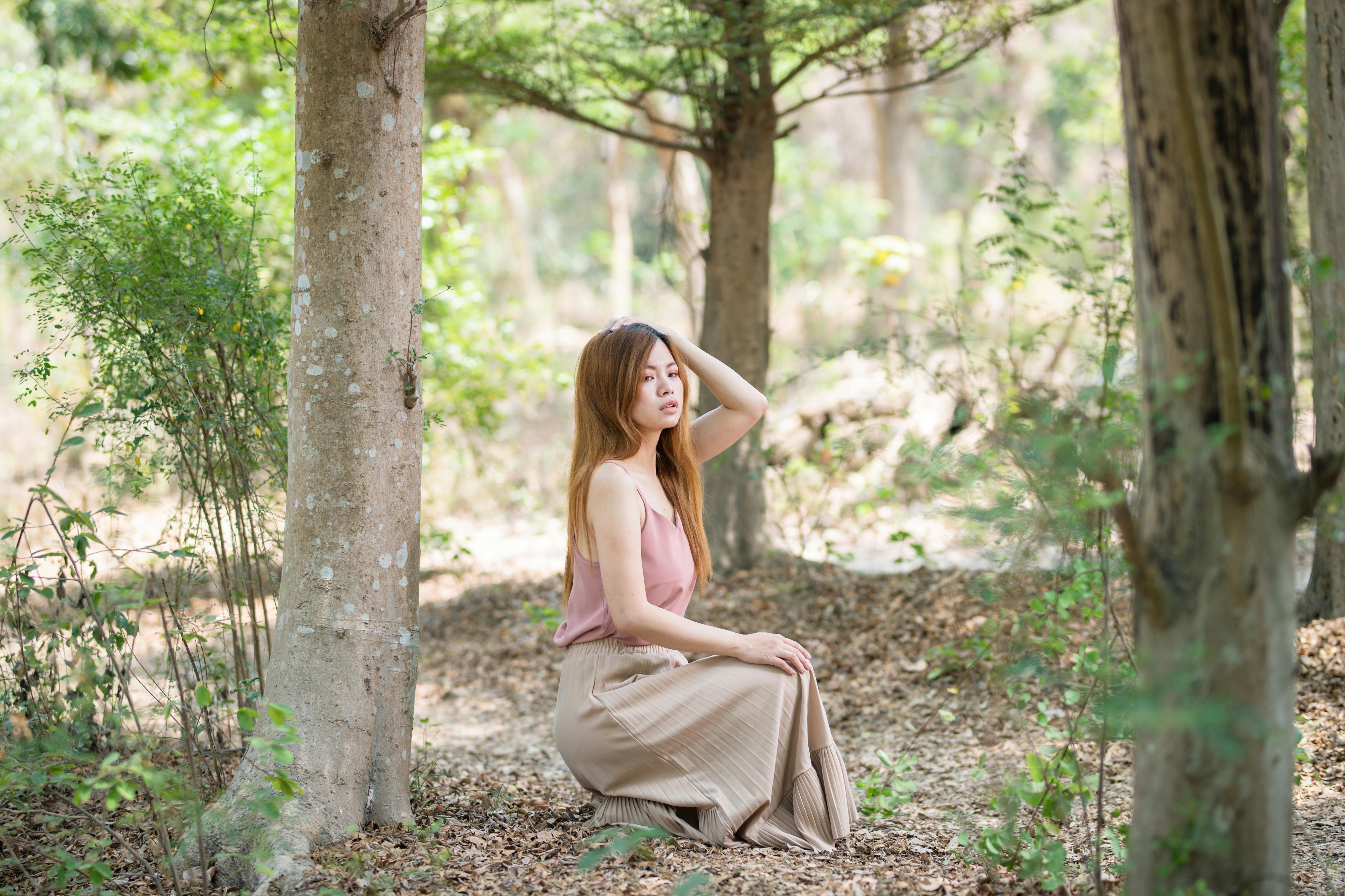 Woman Crouching between Trees · Free Stock Photo