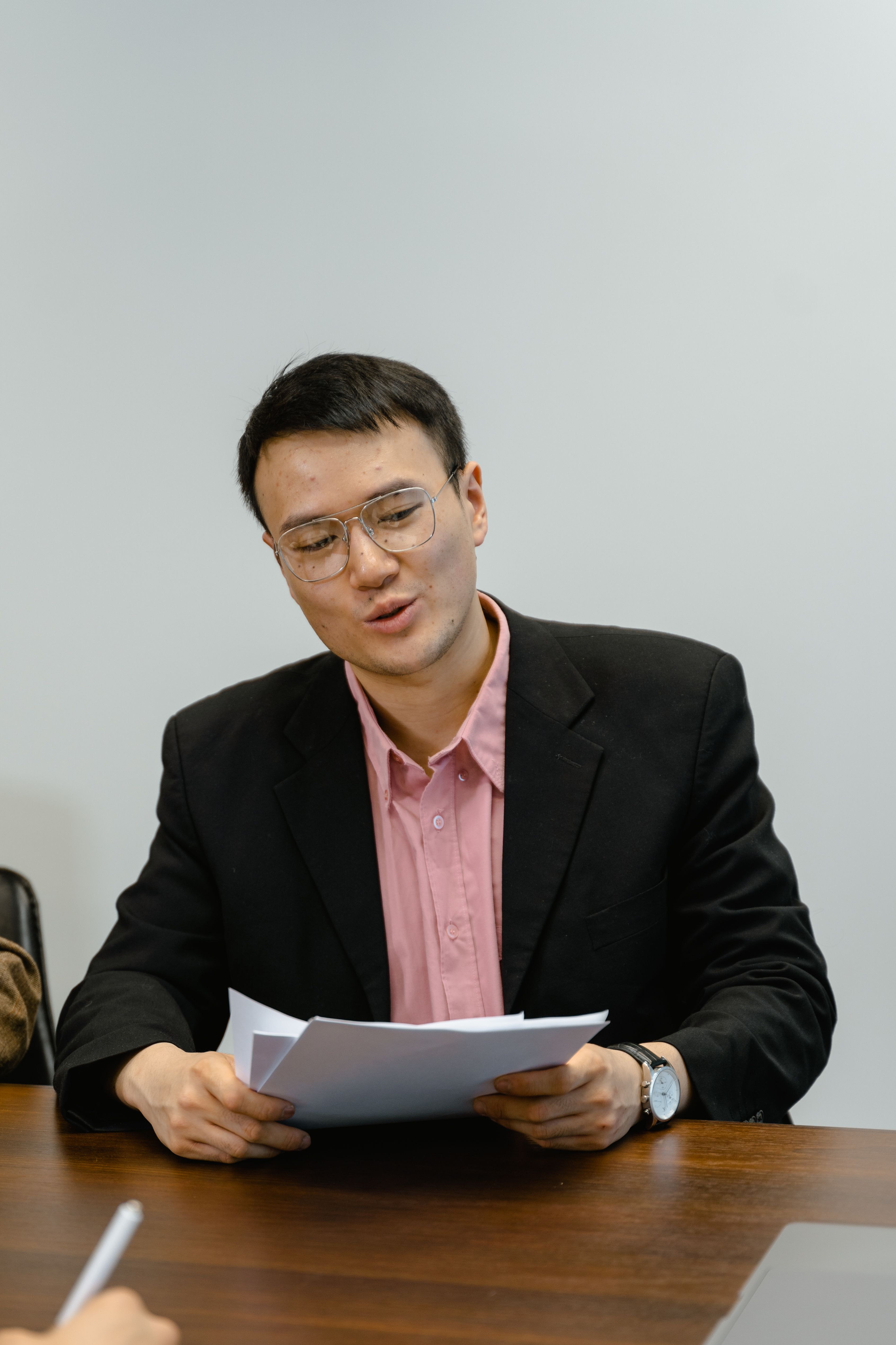 Man in Glasses Talking While Holding Papers · Free Stock Photo