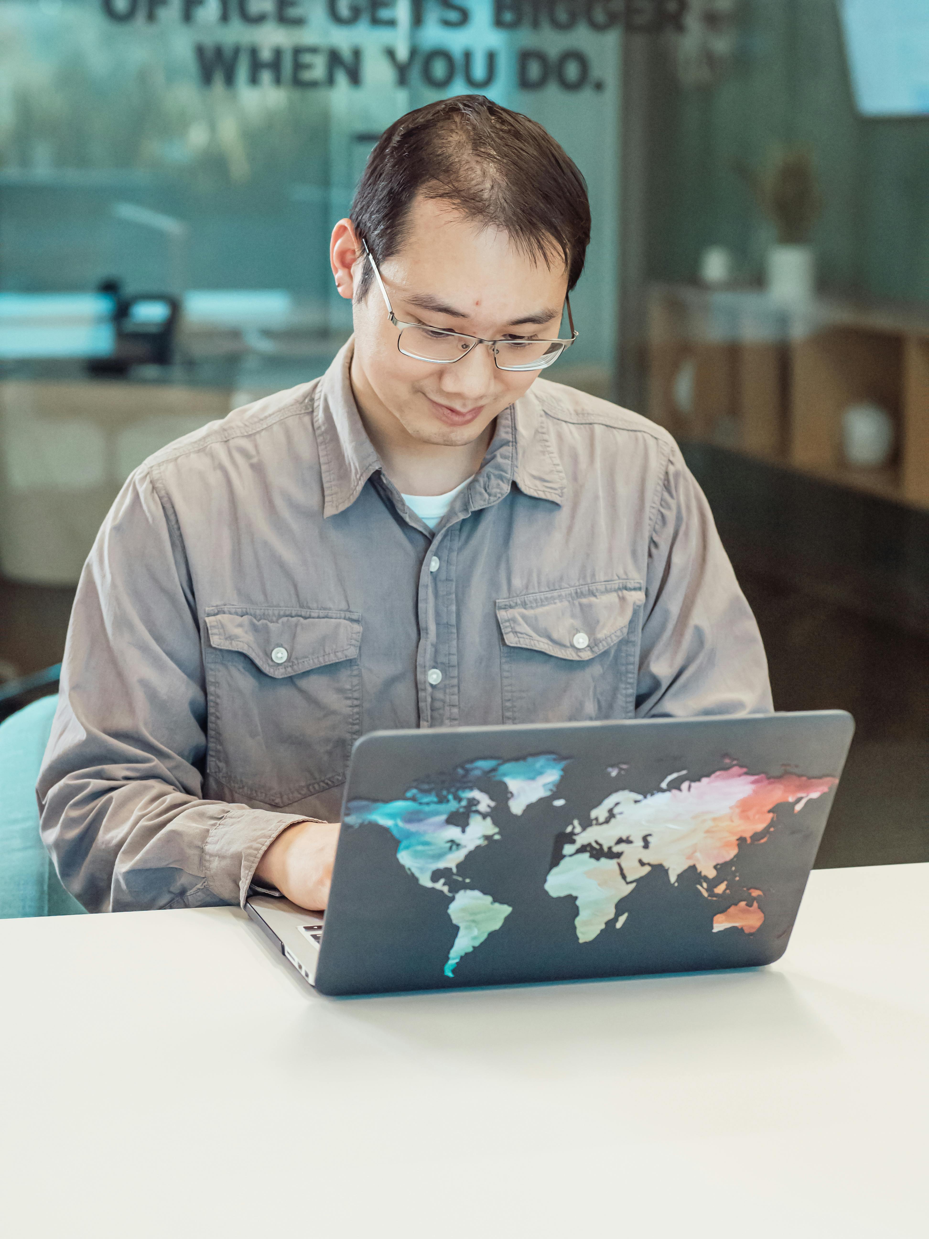 A Man in Gray Sleeves Using a Laptop · Free Stock Photo