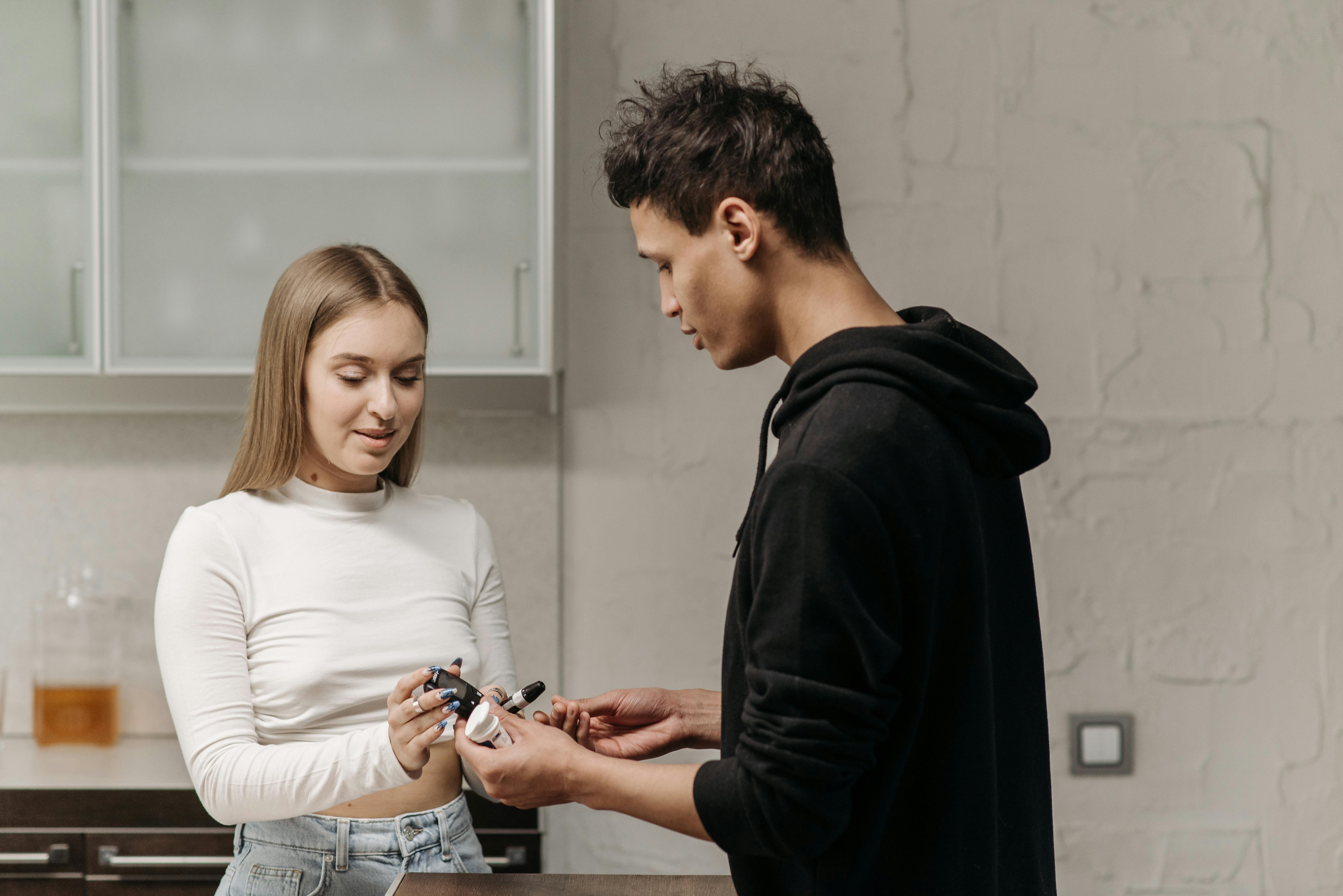A Woman Handing the Glucose Meter to the Man Wearing Black Hoodie ...