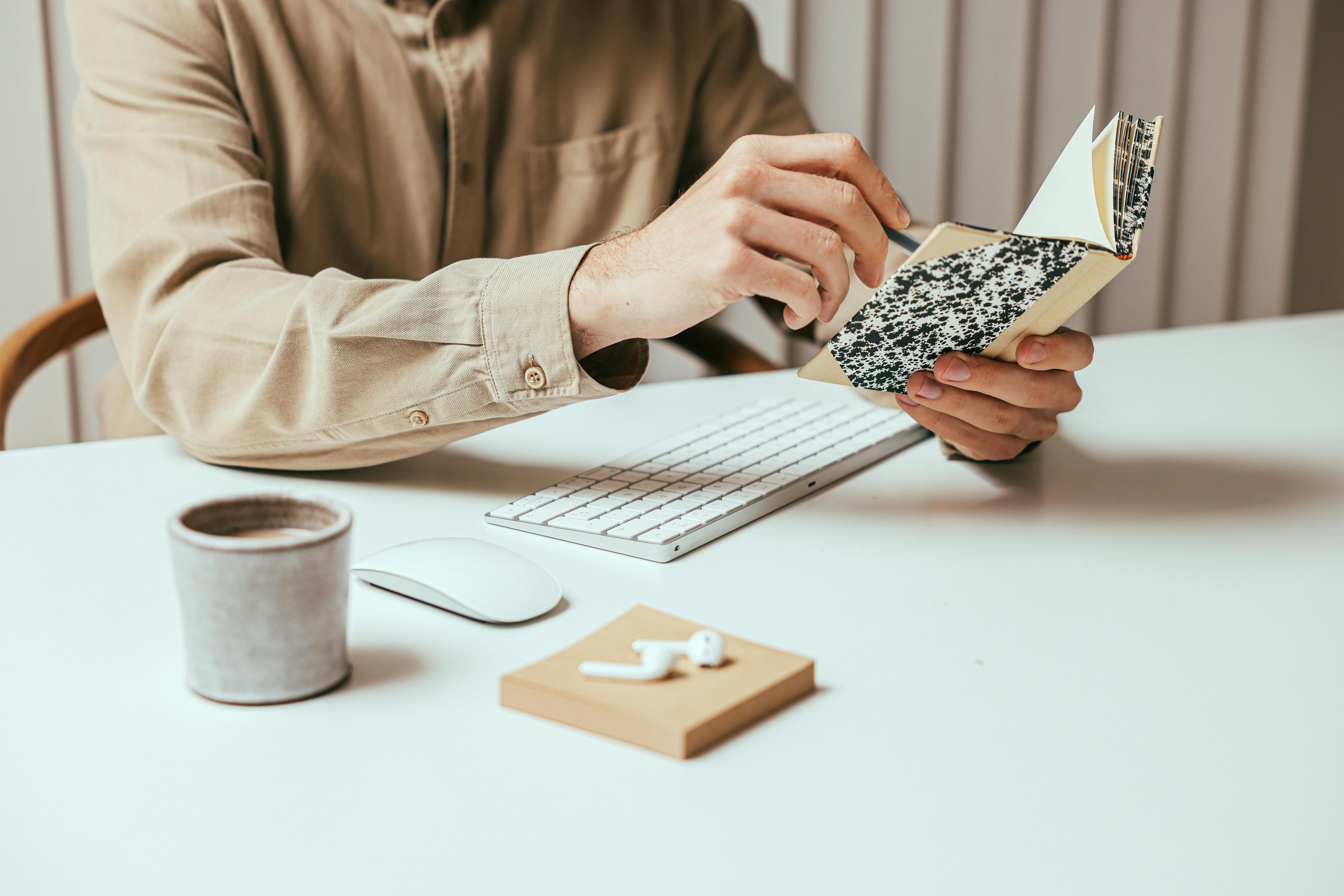 Man Sitting at the Desk and Holding a Notepad · Free Stock Photo