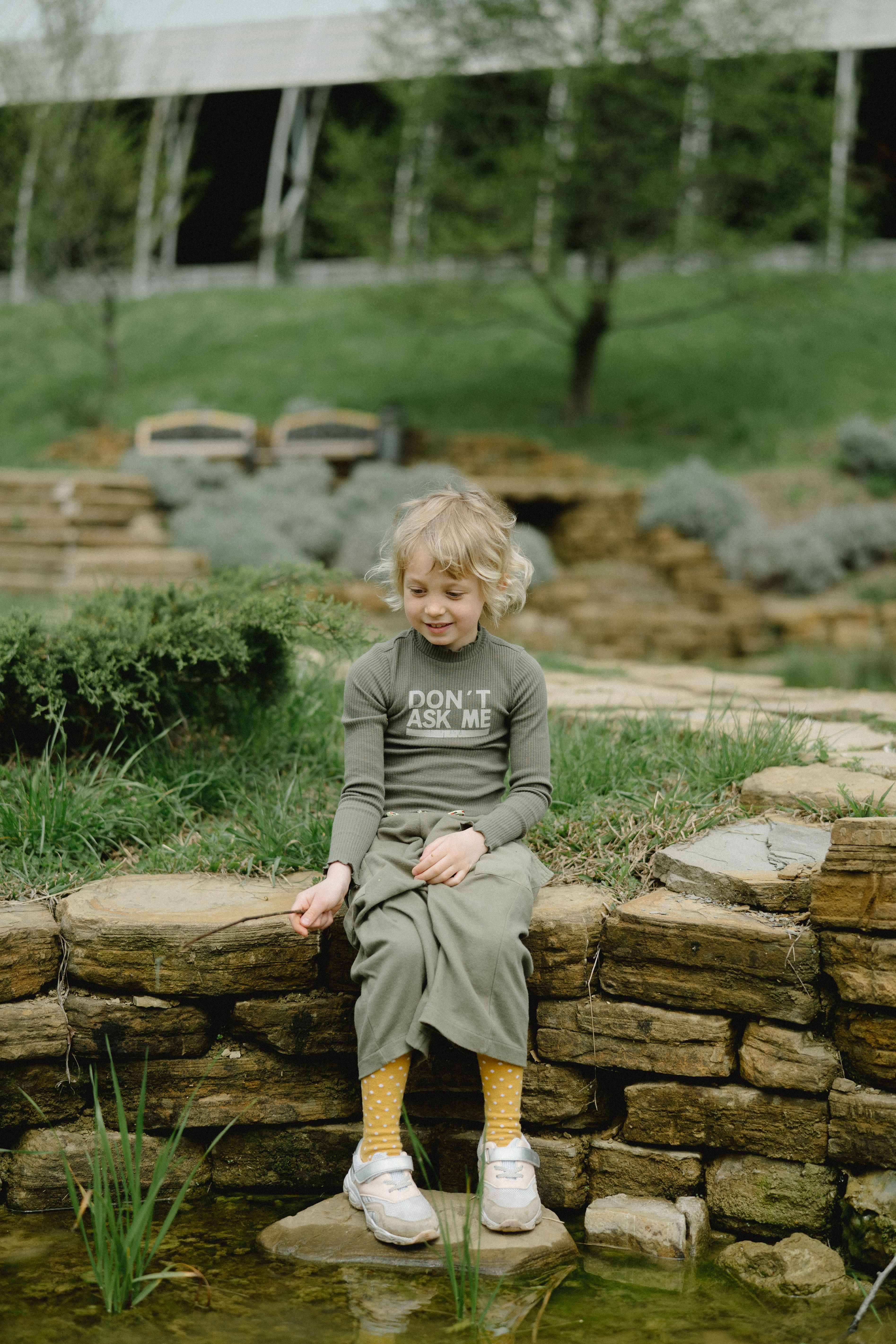Girl in Gray Sweater Sitting on Brown Rocks · Free Stock Photo