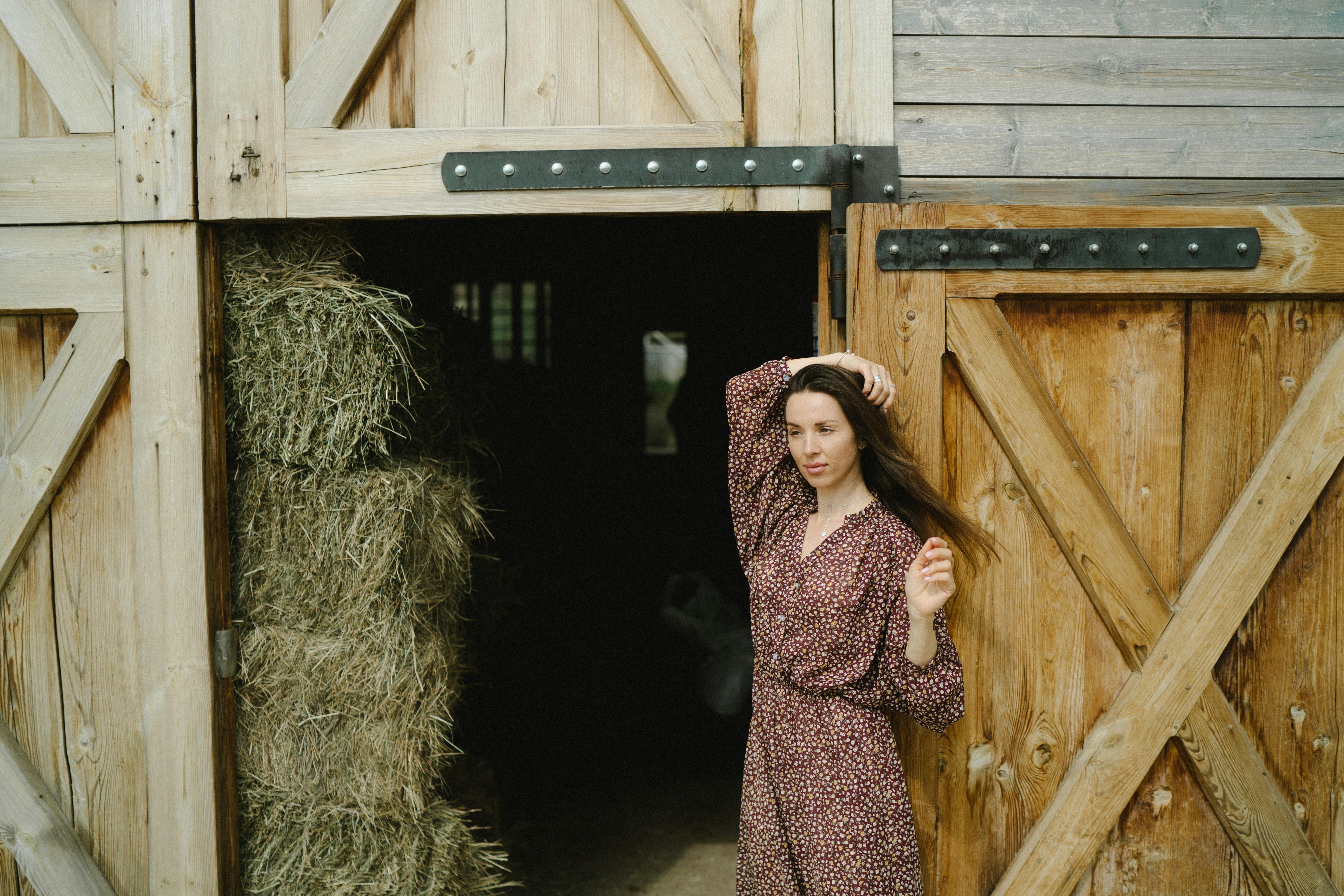 A Woman in a Printed Dress Standing by a Barn Door · Free Stock Photo