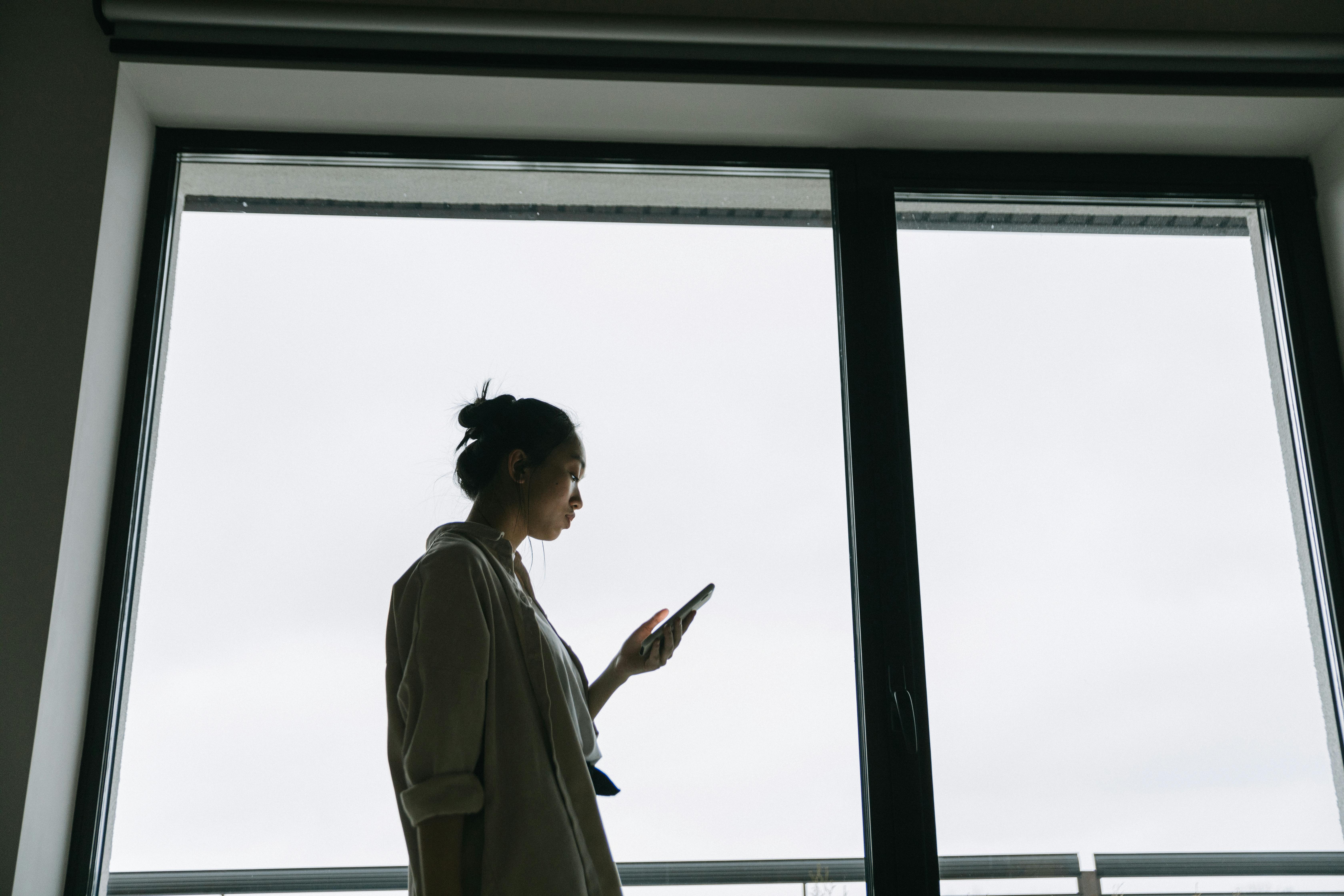 A Woman Standing Near a Glass Window · Free Stock Photo