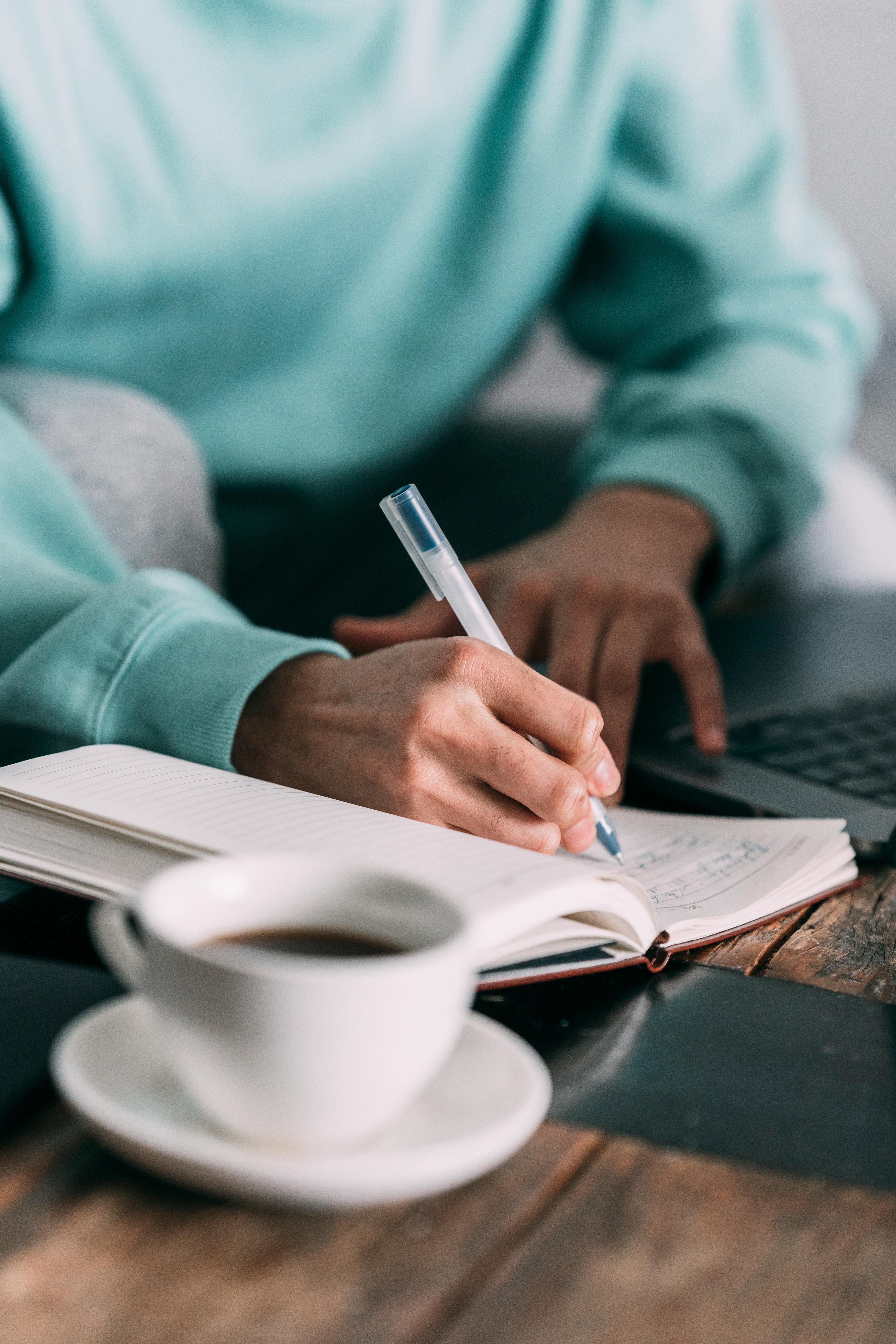 Unrecognizable man writing in notepad · Free Stock Photo