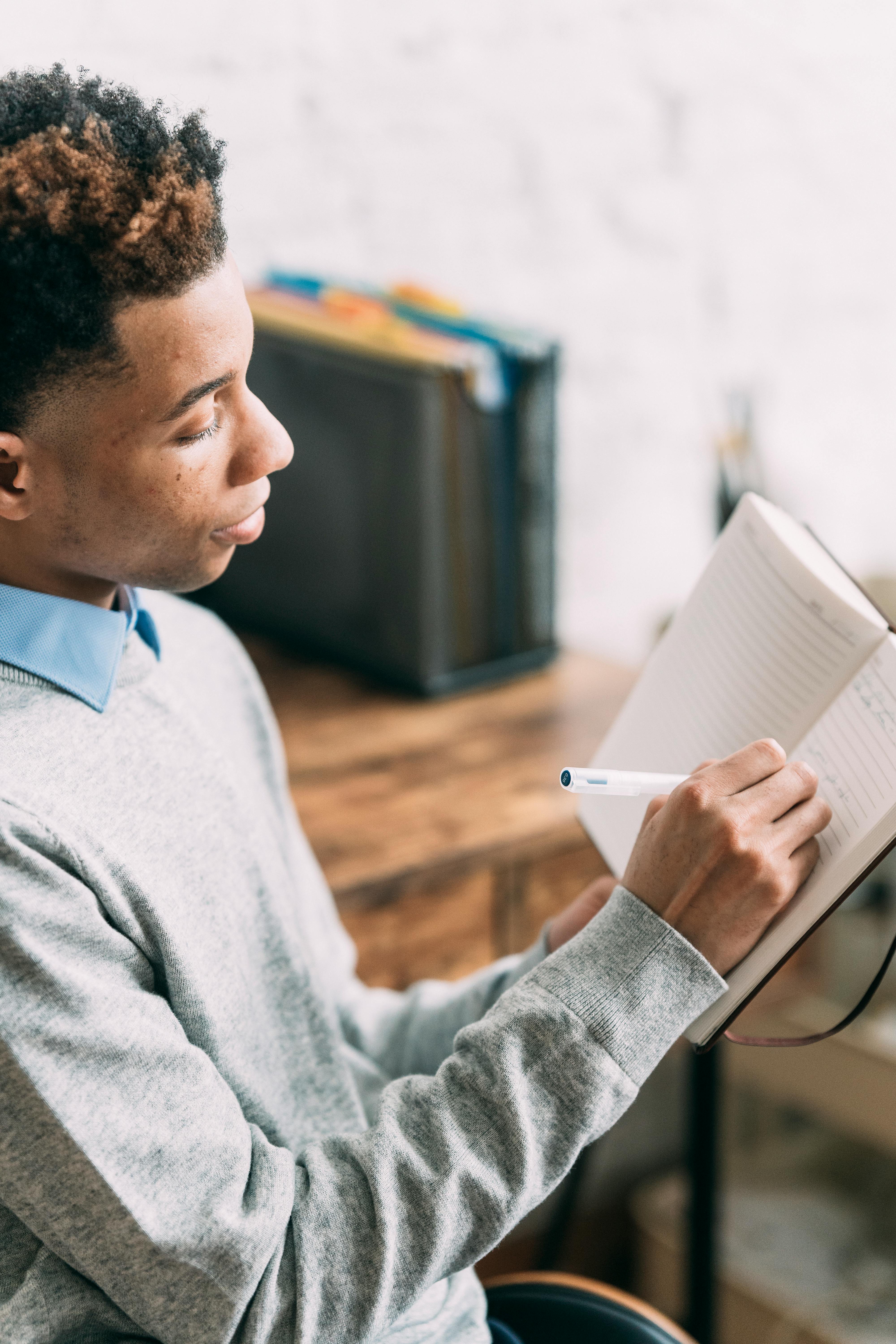 Crop person writing in notebook at workplace · Free Stock Photo