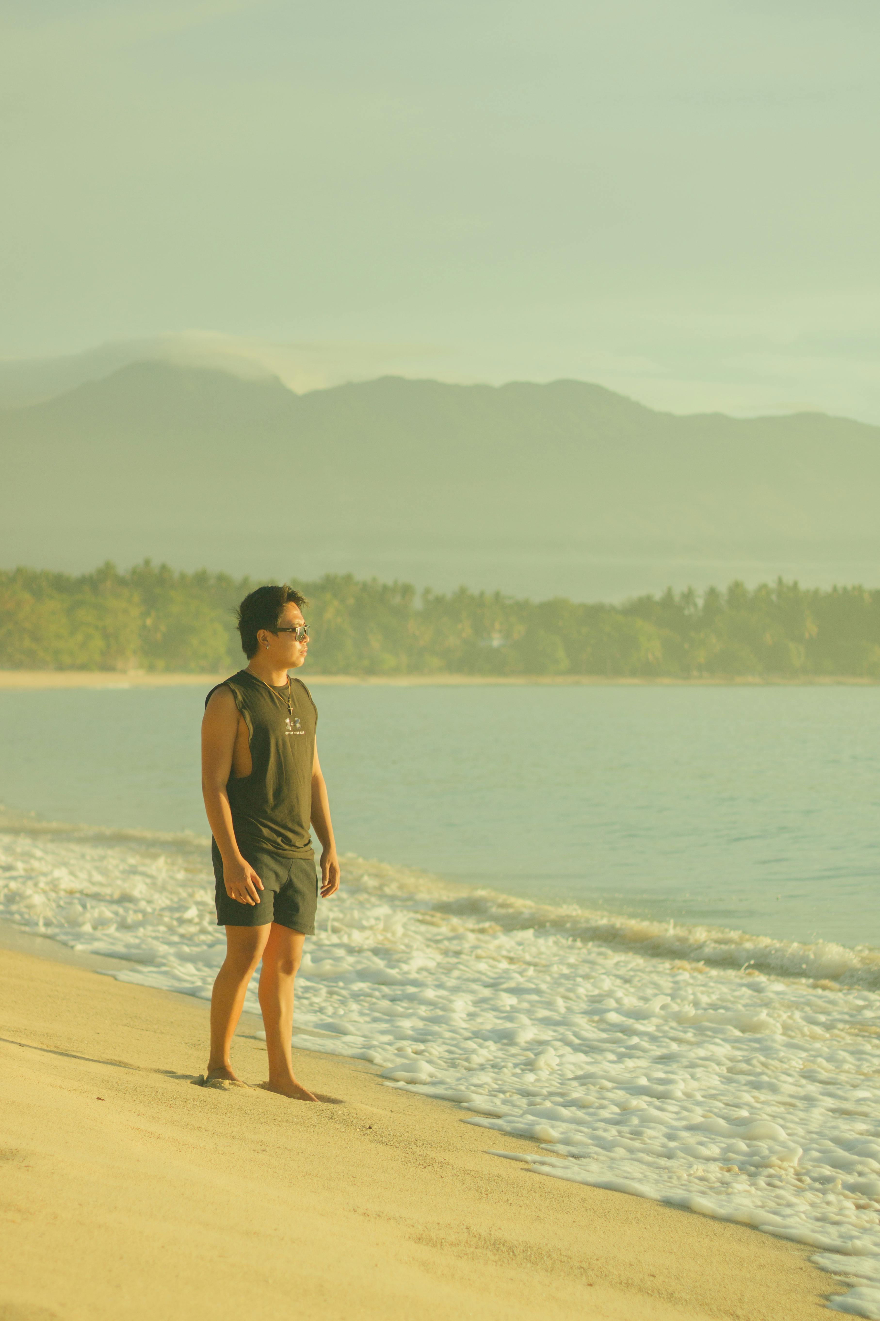 Stylish man model standing on sandy coast near sea · Free Stock Photo