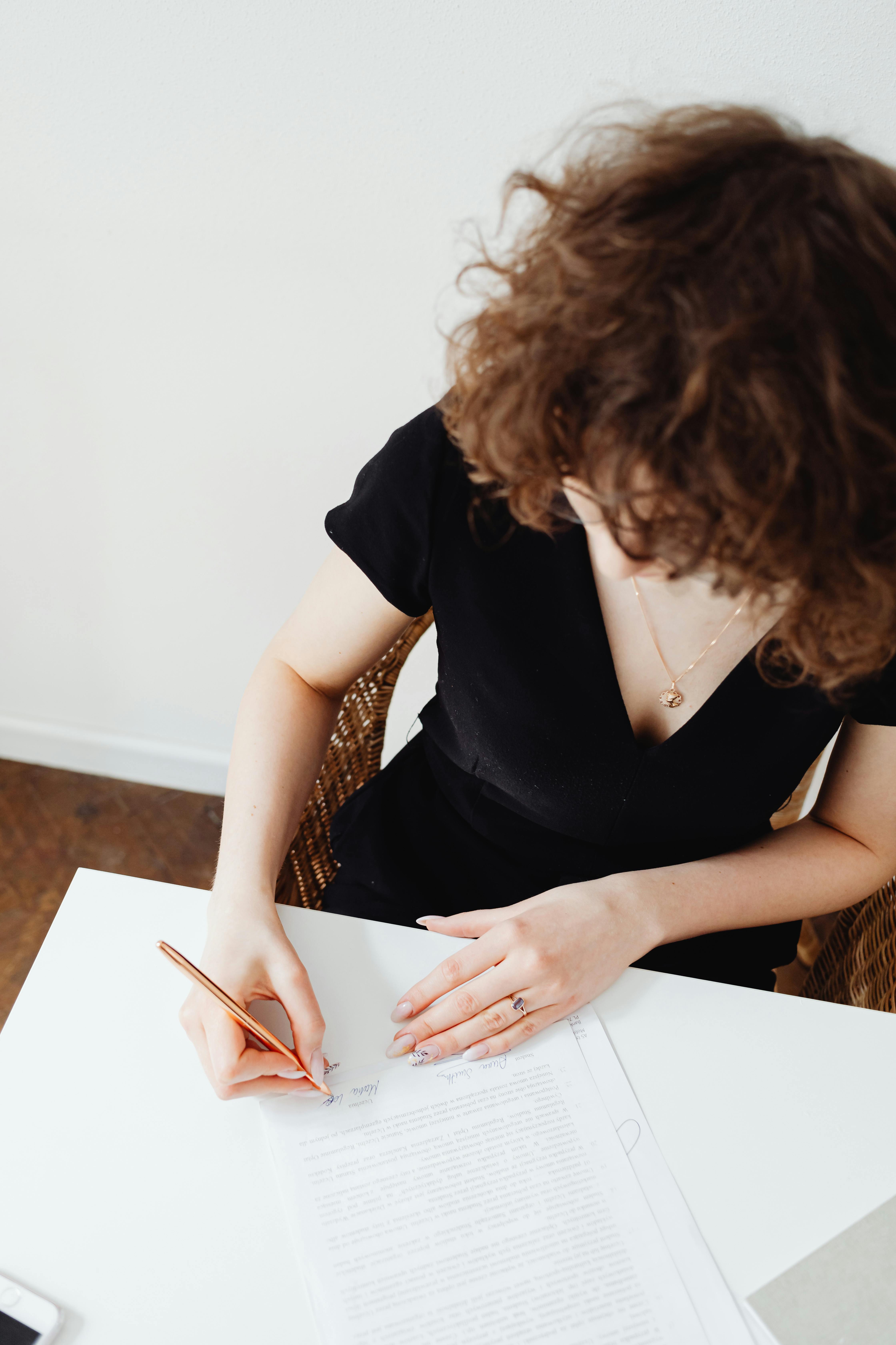 Woman Signing on White Paper · Free Stock Photo