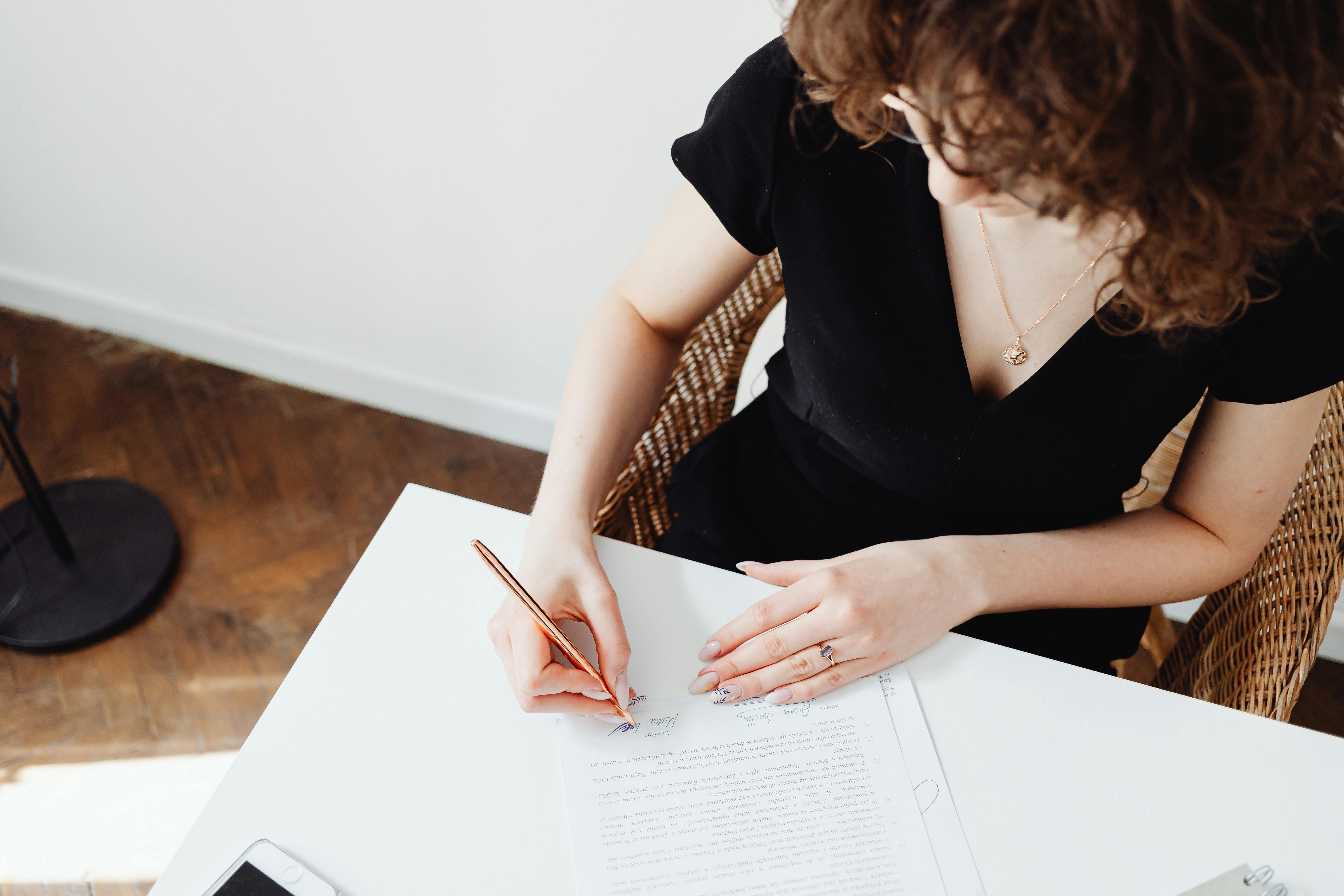 A Woman Signing a Document · Free Stock Photo