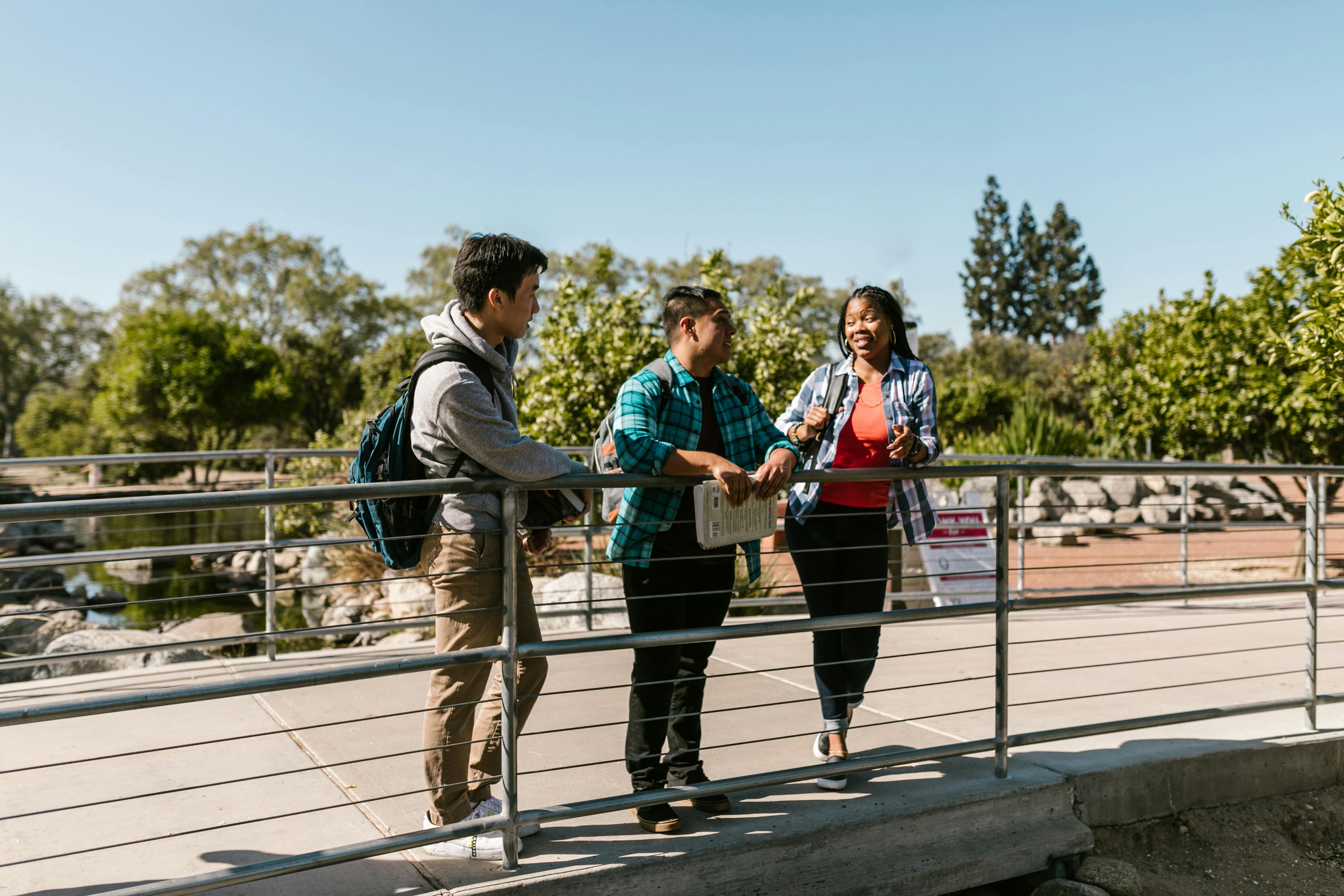 College Students Standing on a Footbridge · Free Stock Photo